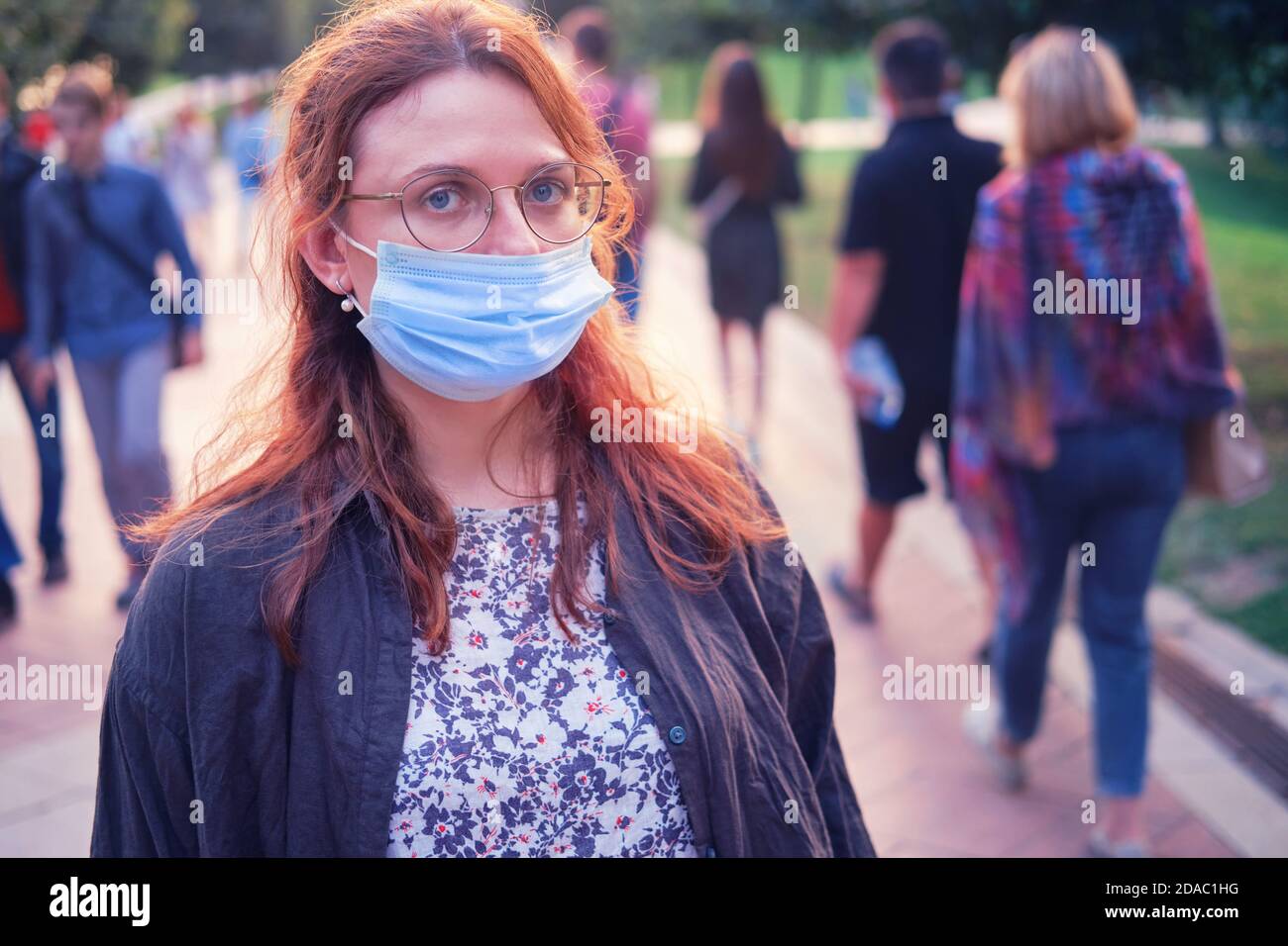 Woman in face mask stands on the street in a crowd of people Stock ...