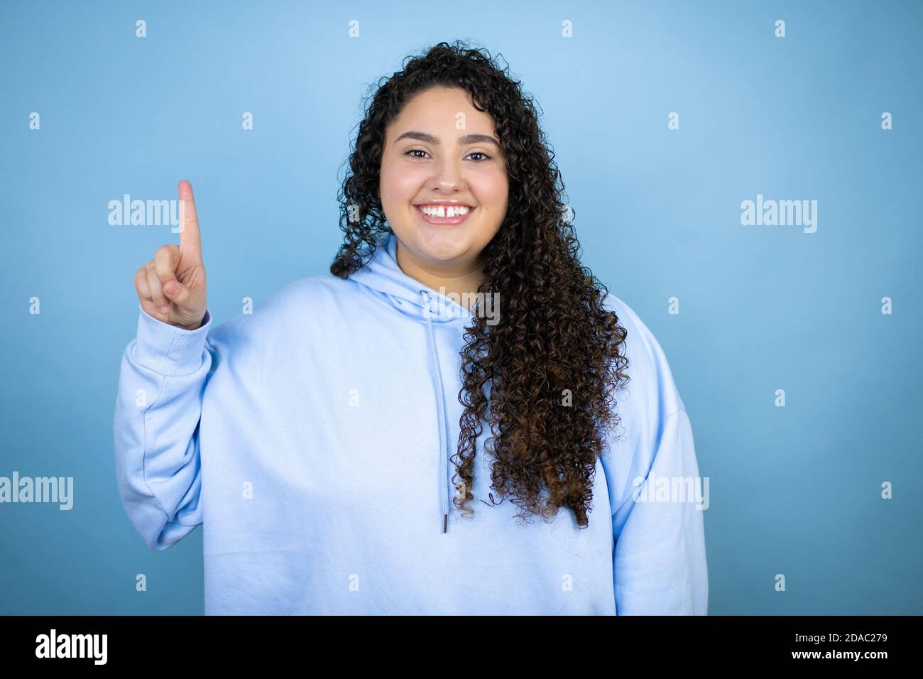 Young beautiful woman wearing casual sweatshirt over isolated blue ...