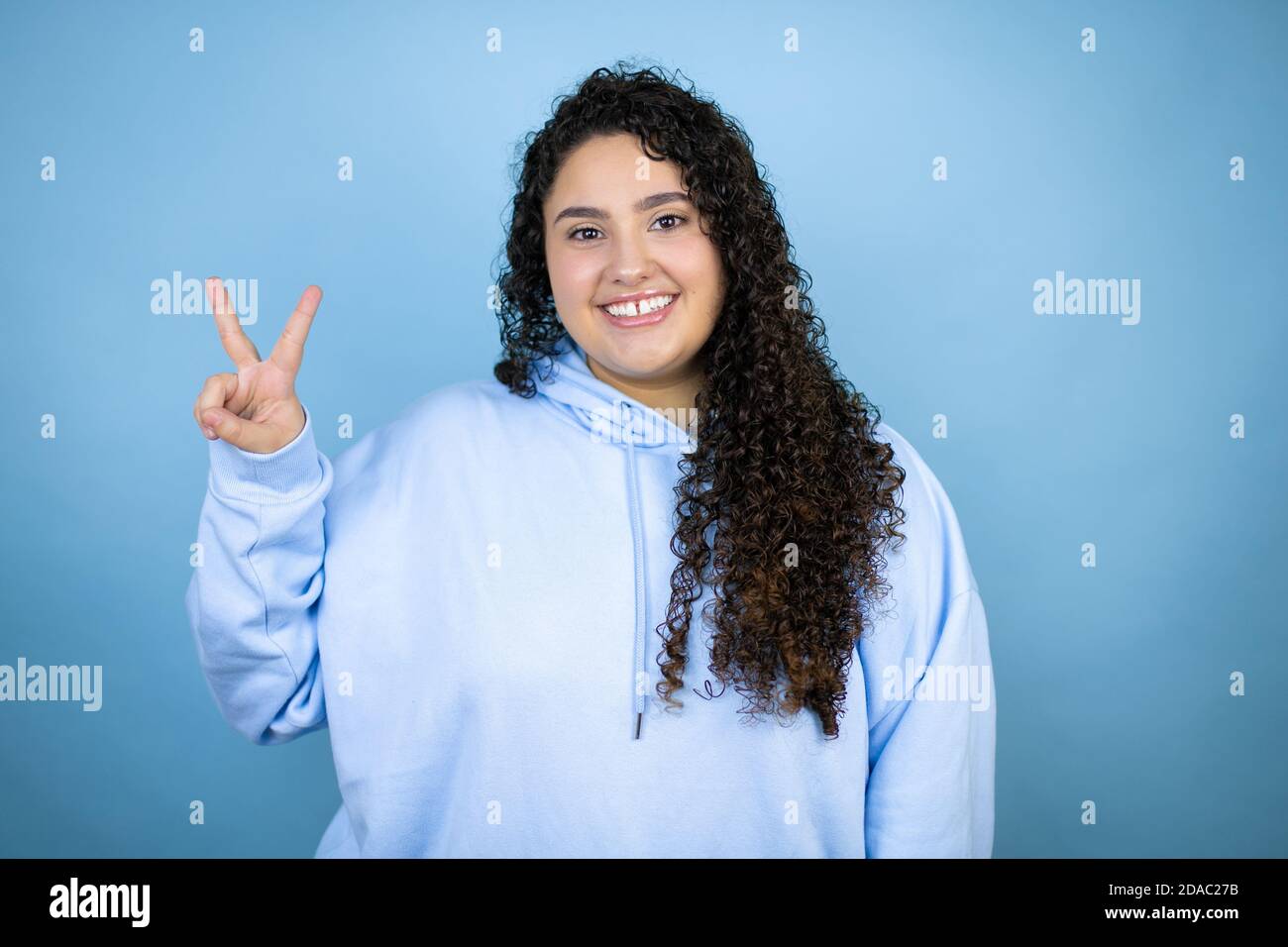 Young beautiful woman wearing casual sweatshirt over isolated blue ...