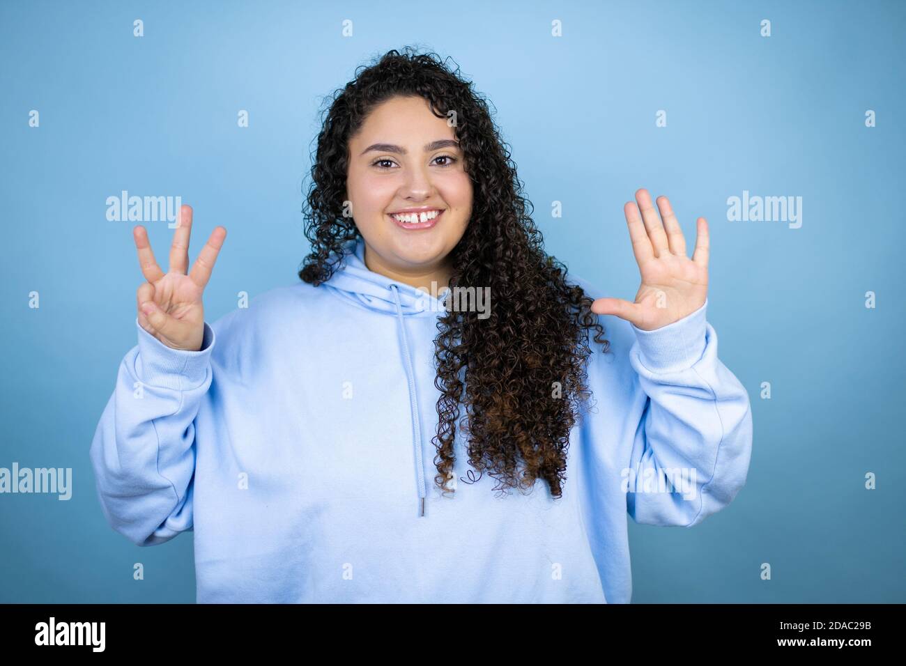 Young beautiful woman wearing casual sweatshirt over isolated blue ...