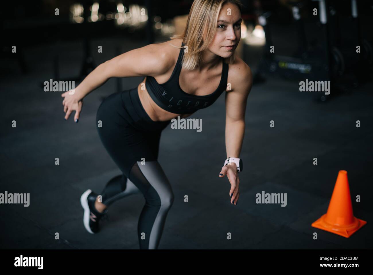 Sporty young woman runner with perfect athletic body posing at gym with ...