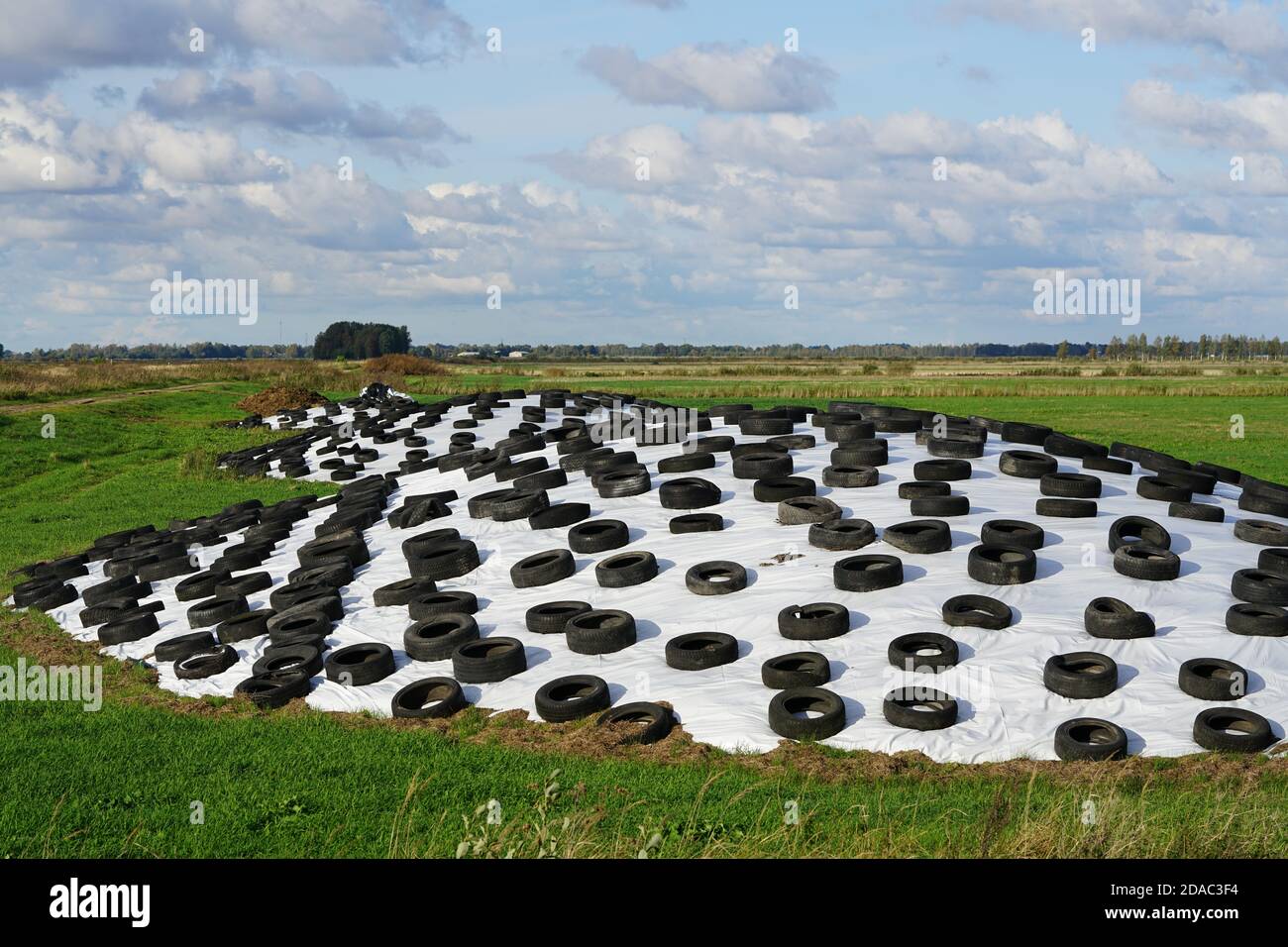 large stack of silage on field covered with plastic film and used tires ...