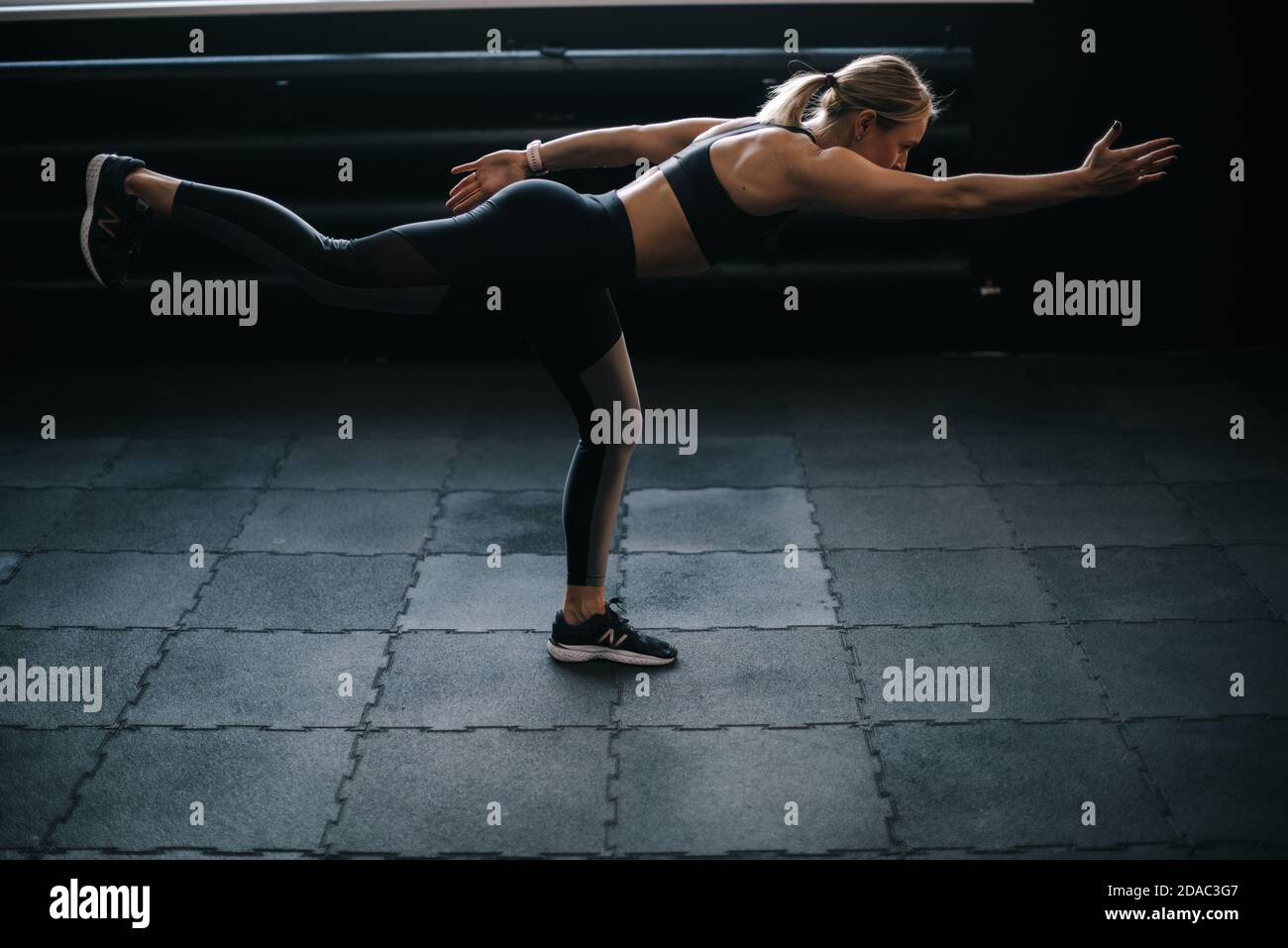 Fitness young woman doing warrior three yoga pose standing on one leg ...