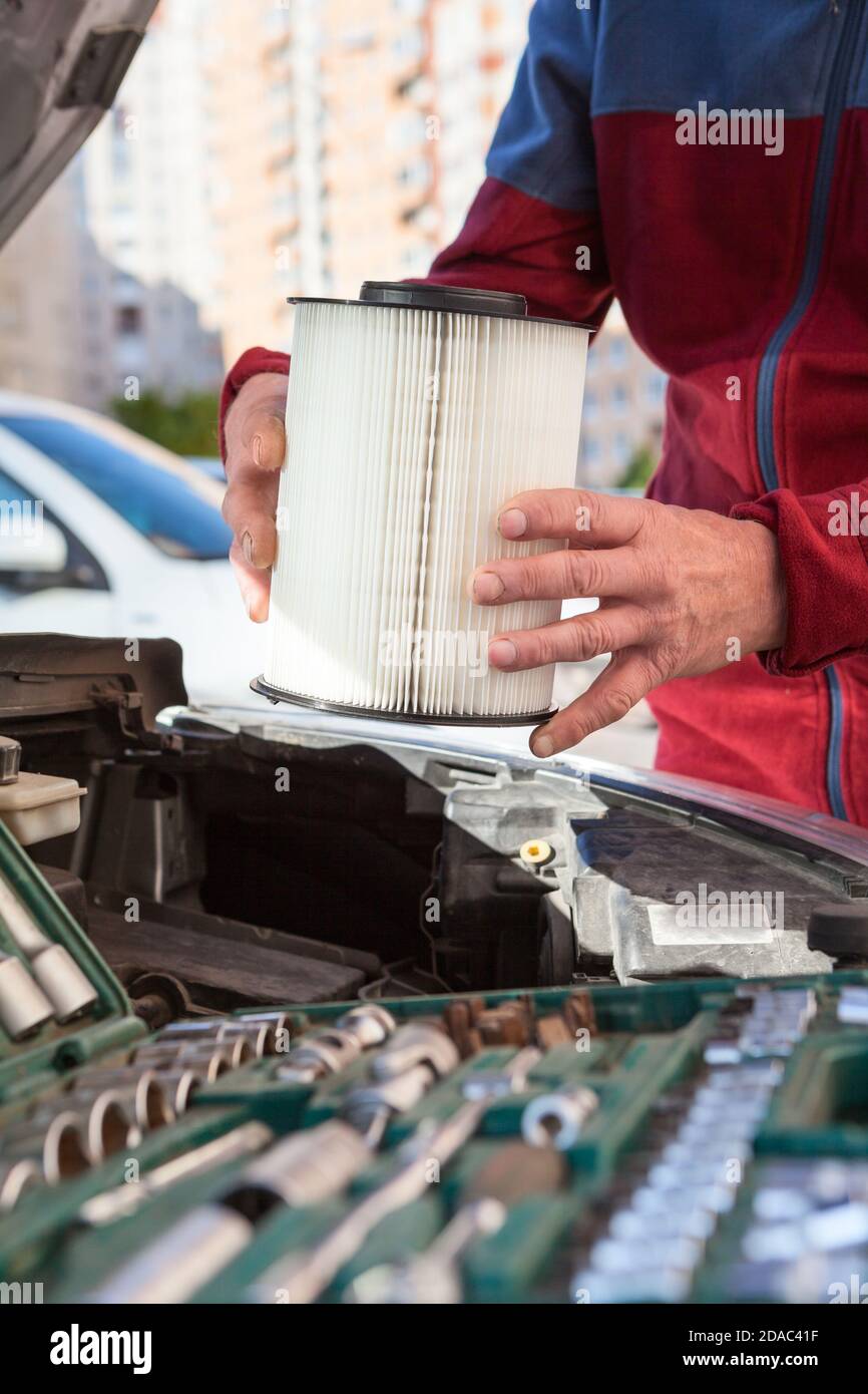 Driver hands inserting air cartridge inside airbox of car engine, close ...
