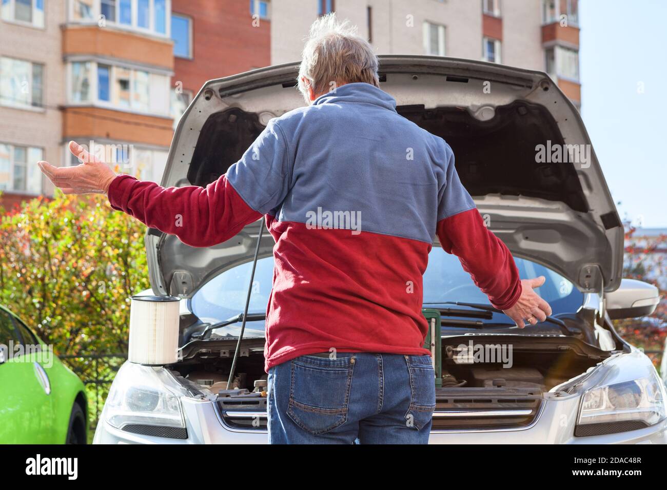 Senior Caucasian man throw up his hands while standing in front of car ...