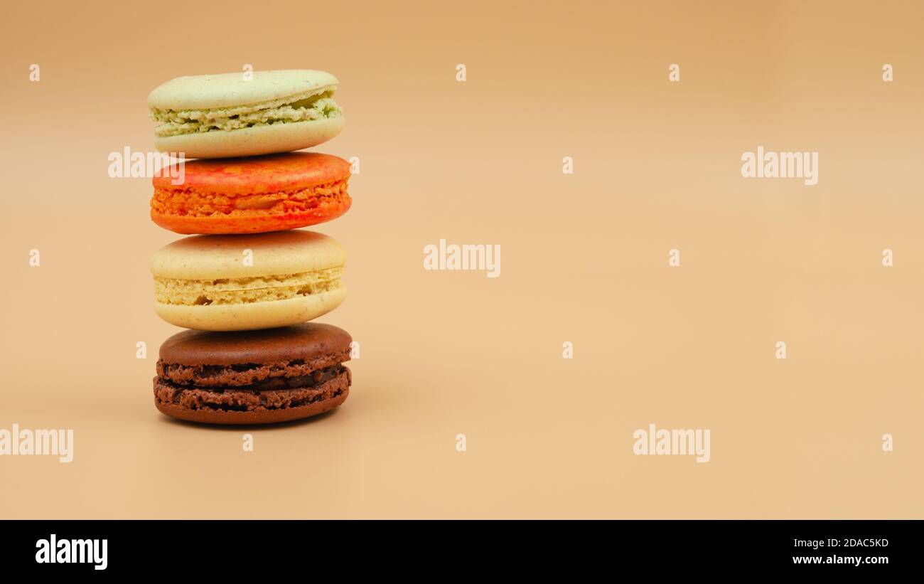 Four brightly colored stacked up French Macarons on peach background ...