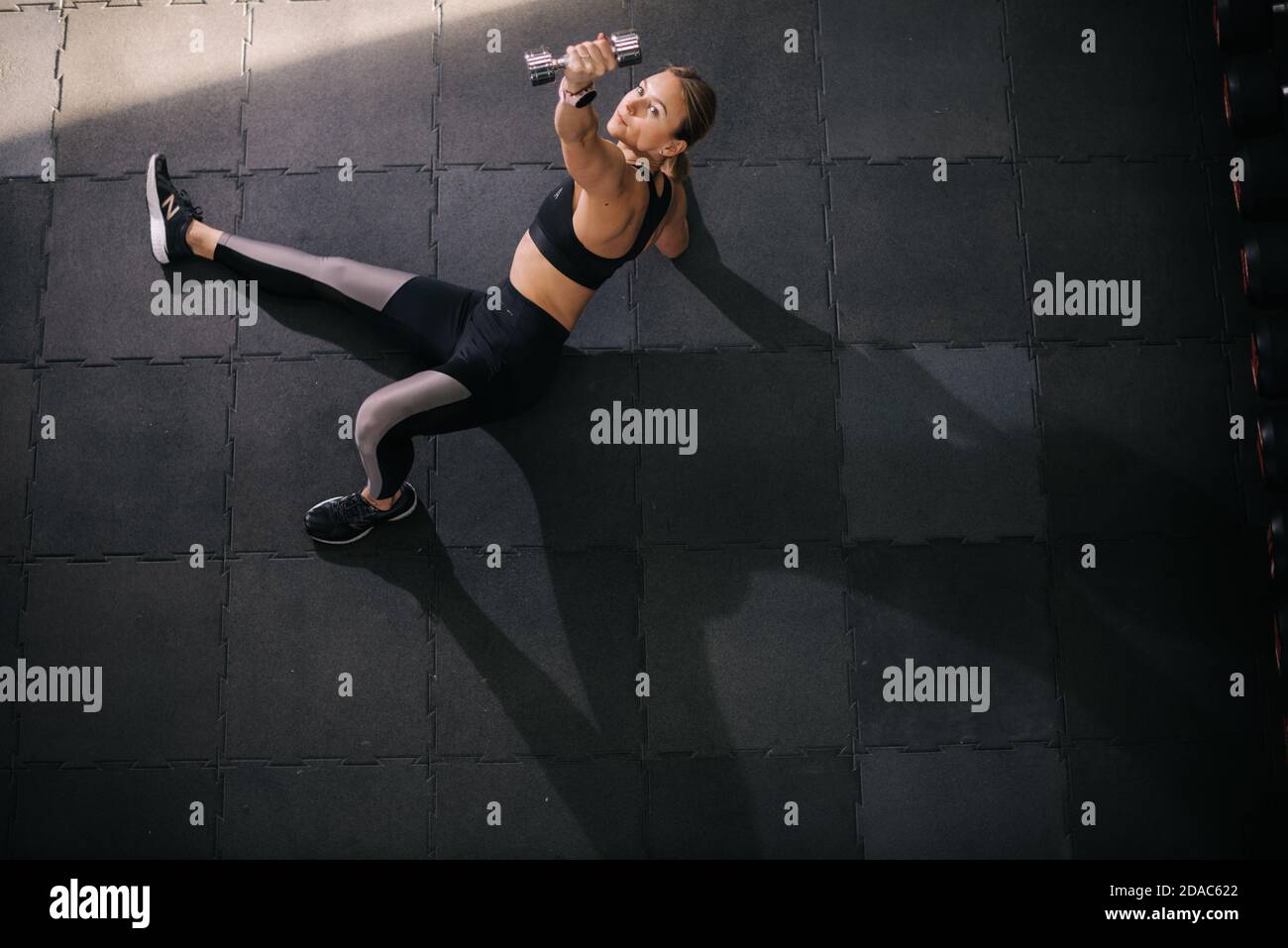 Top down view of strong young woman with athletic body lying on floor ...