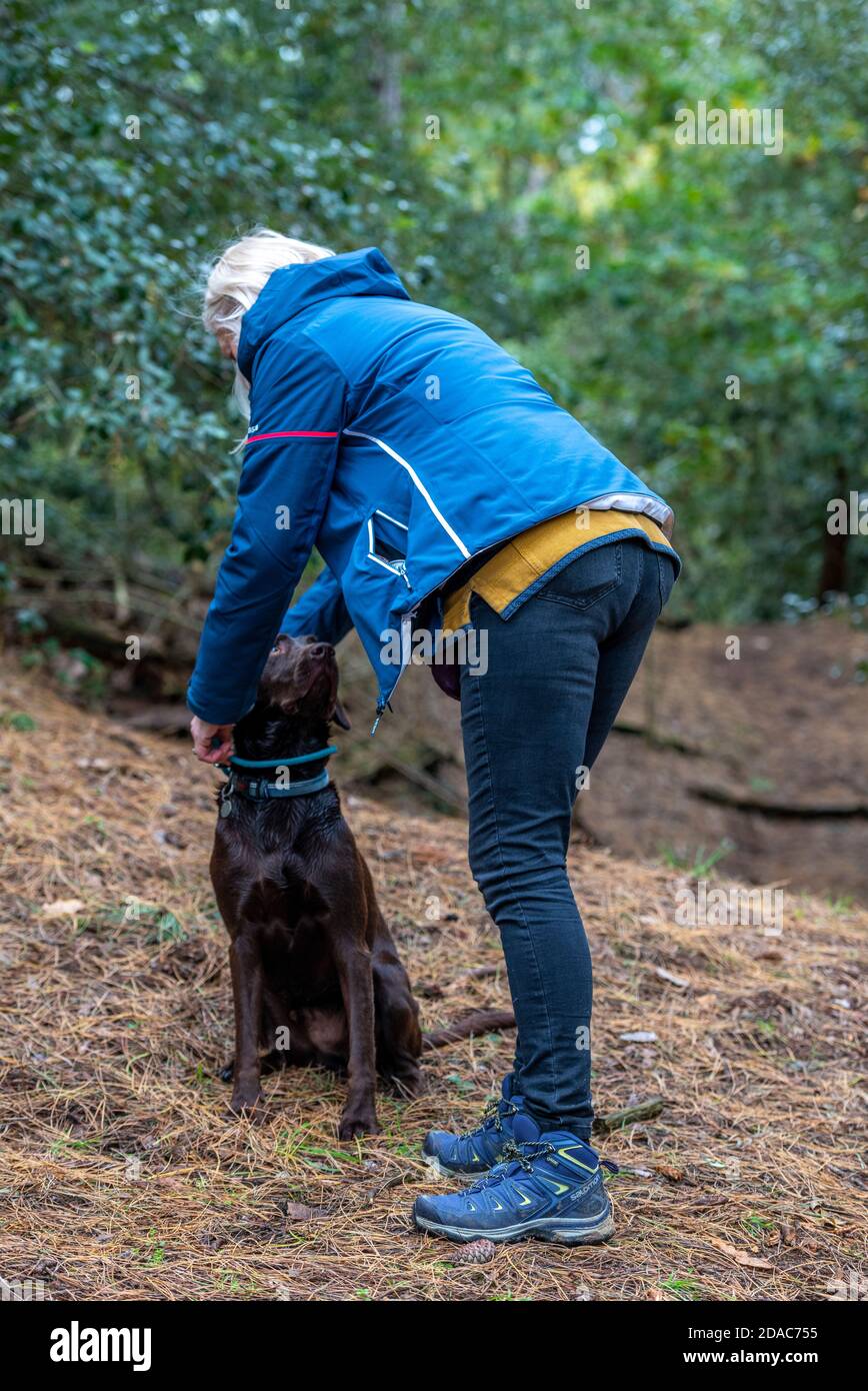a woman putting a dog back onto it's lead while walking in the ...