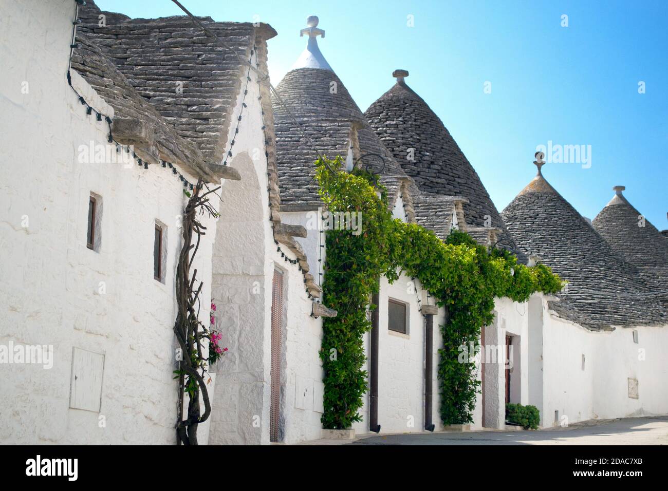 Street with unique white buildings with conical roof called "Trulli" in ...