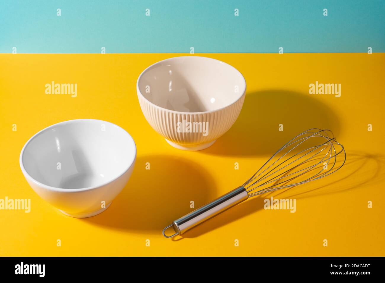 Two empty deep bowls and a metal whisk on bright background Stock Photo ...