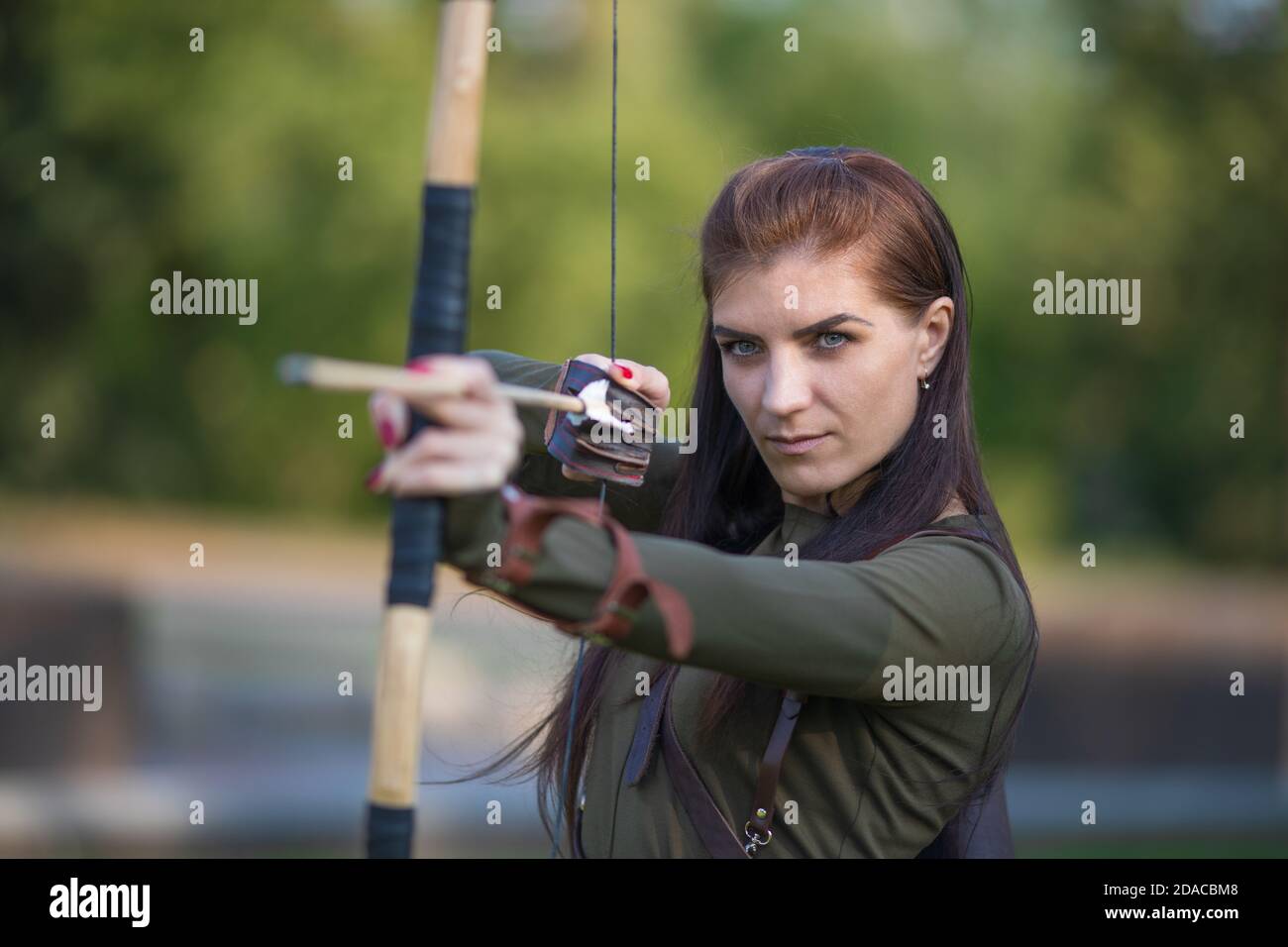 Archery woman with bow shooting on the forest Stock Photo - Alamy