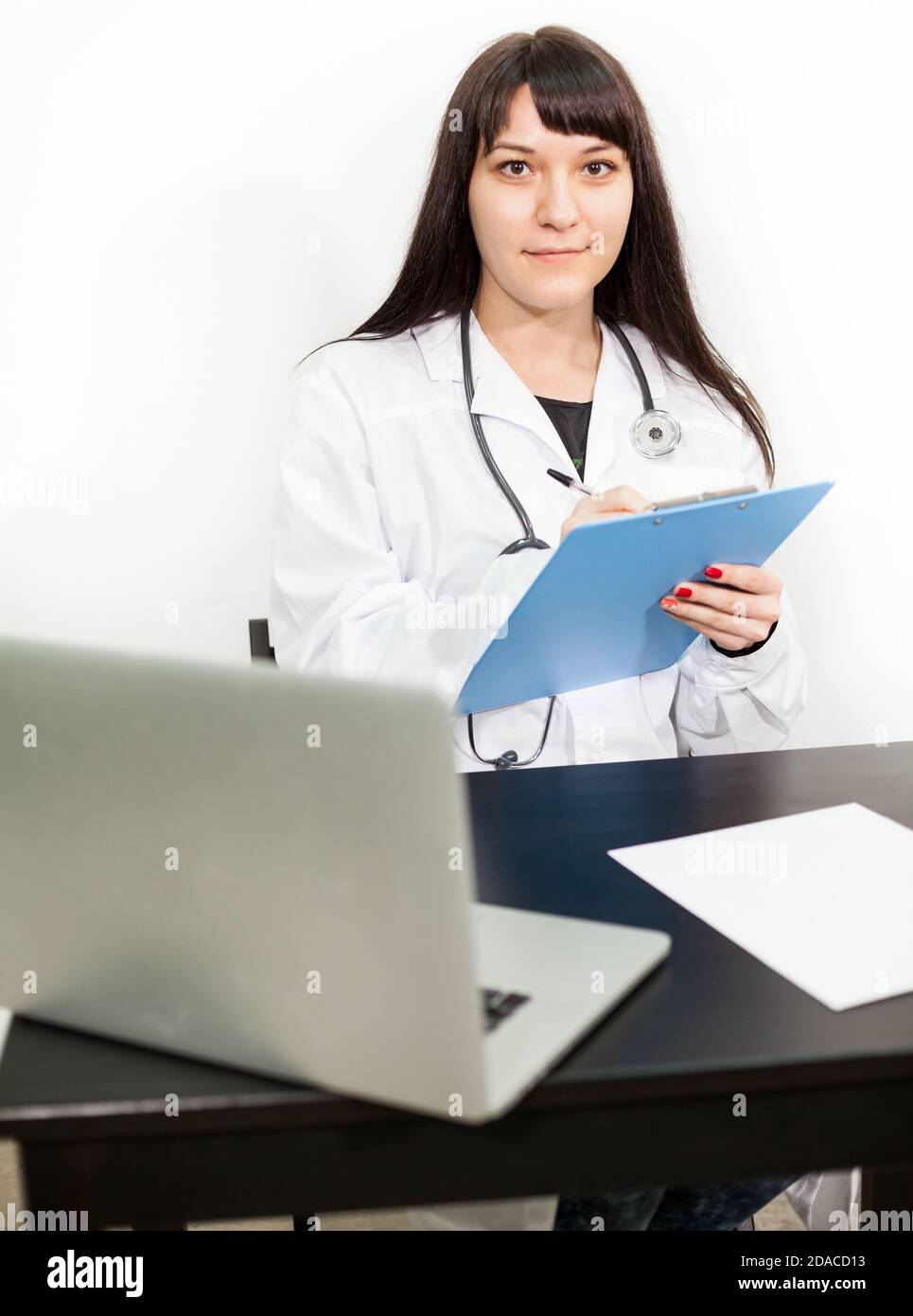 Portrait of young beautiful woman doctor or intern sitting at the desk ...