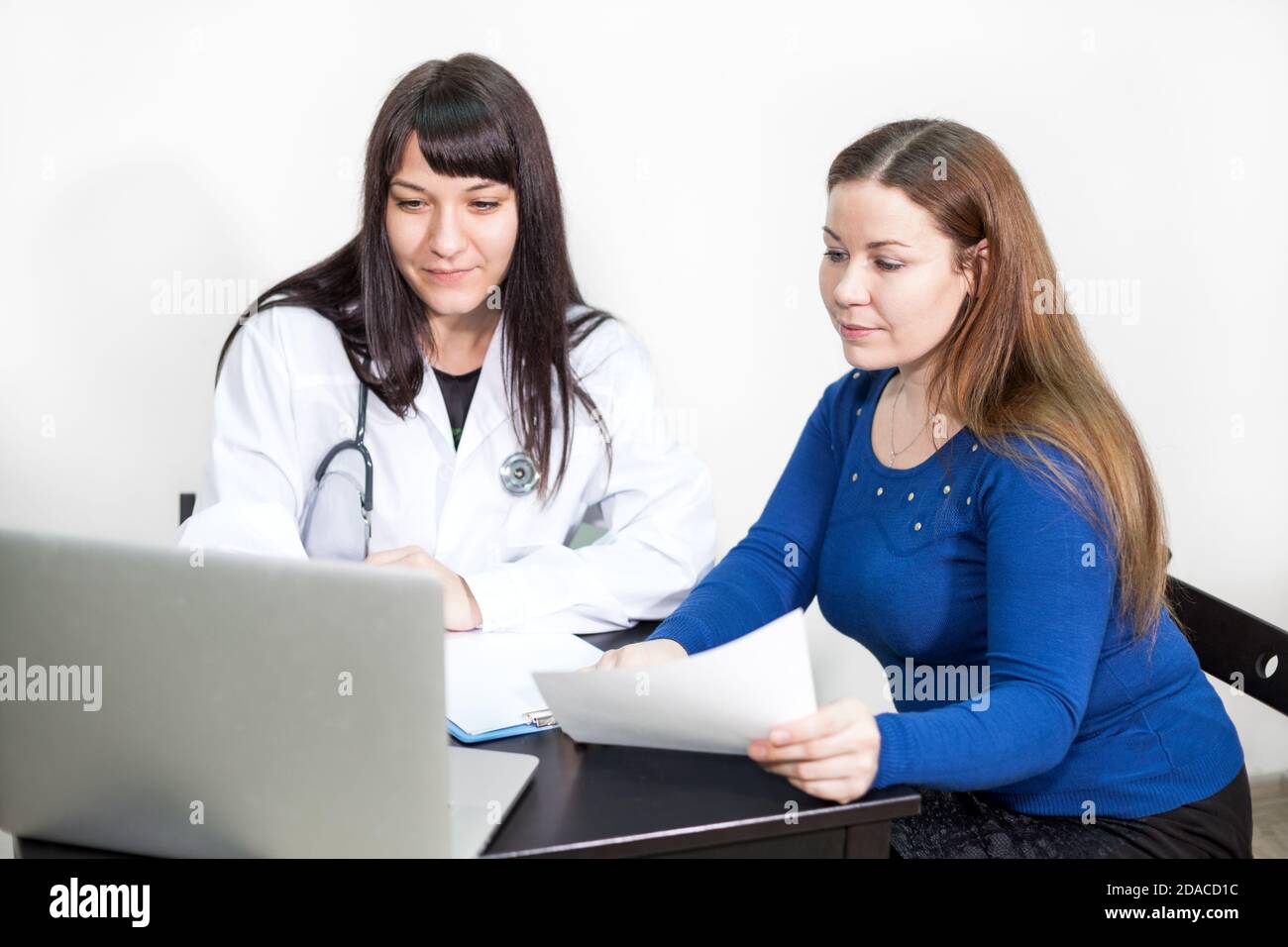 Doctor and patient discuss test results at the desk, looking at screen ...