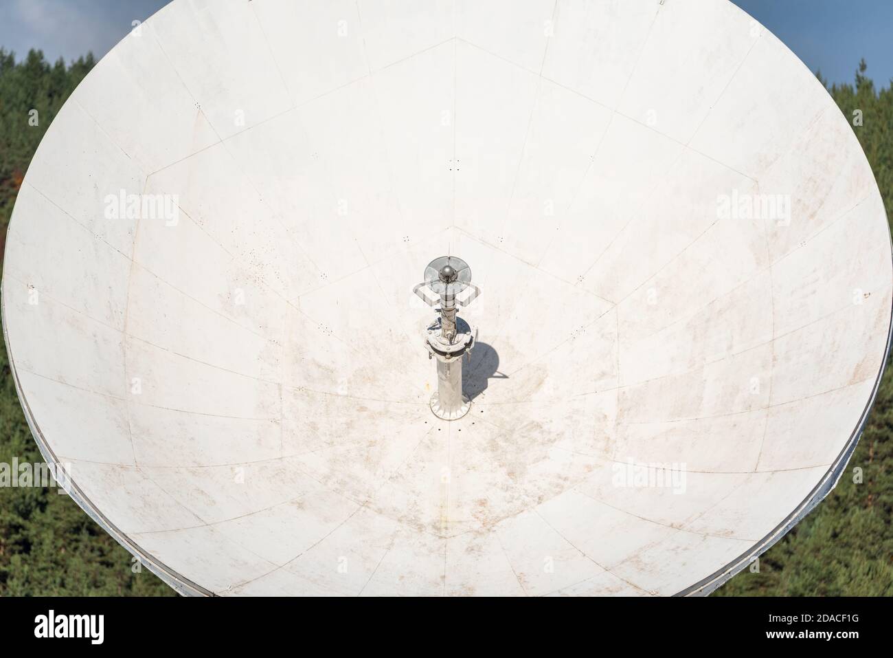 Detail of a giant radio telescope dish pointed skyward on clear blue ...