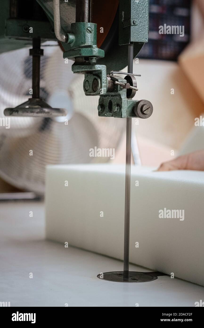 Vertical shot of a foam cutter machine, cutting through an upholstery ...