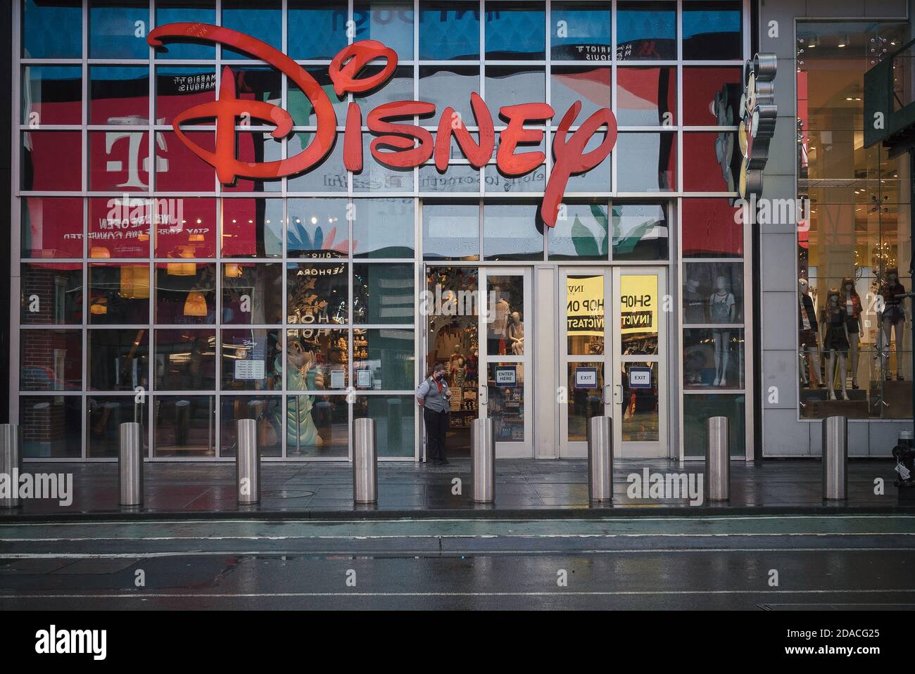 A store clerk wearing a face mask stands at the entrance of an empty ...
