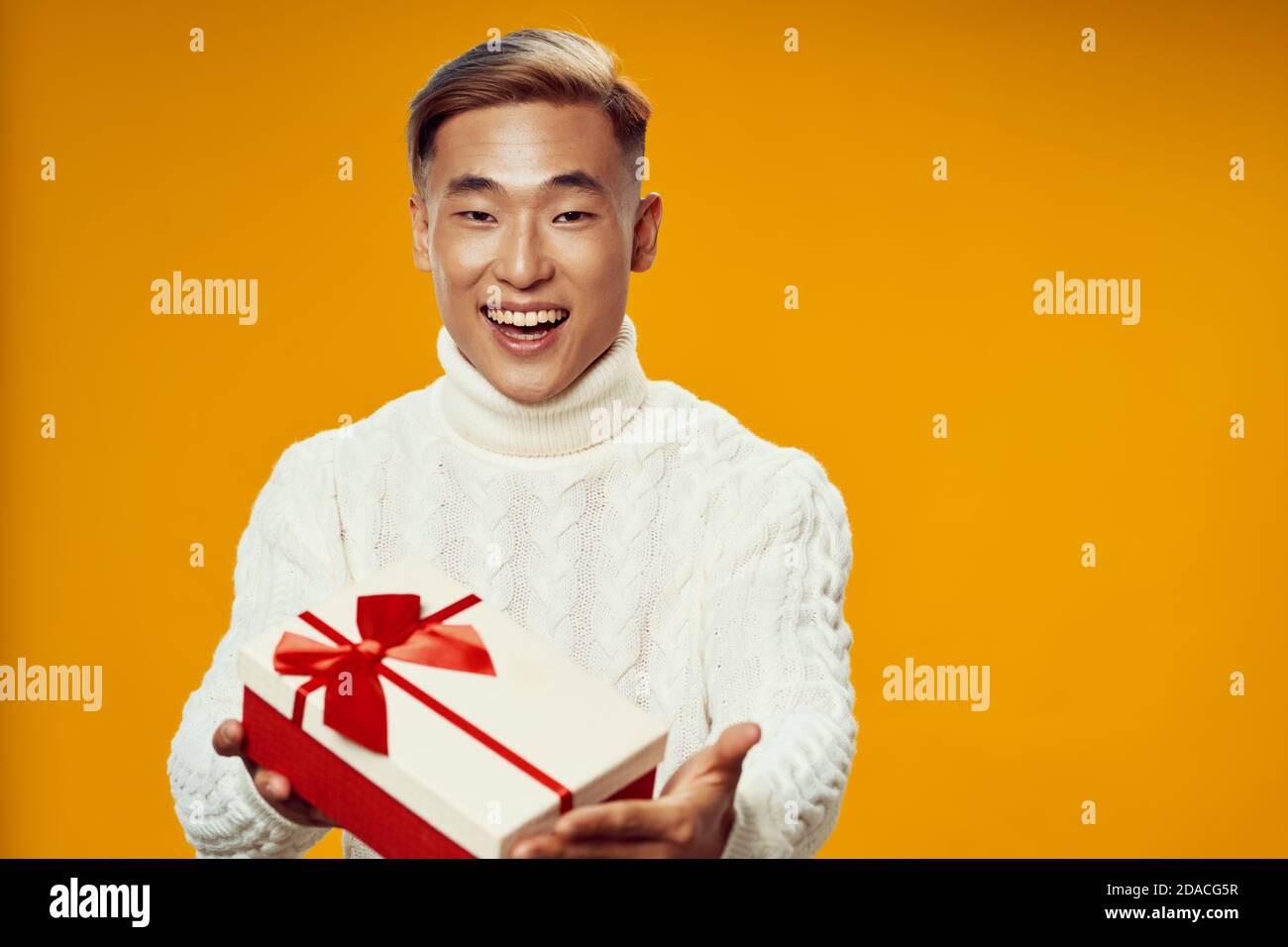 Happy man with a gift in a box on a yellow background smiling Stock ...