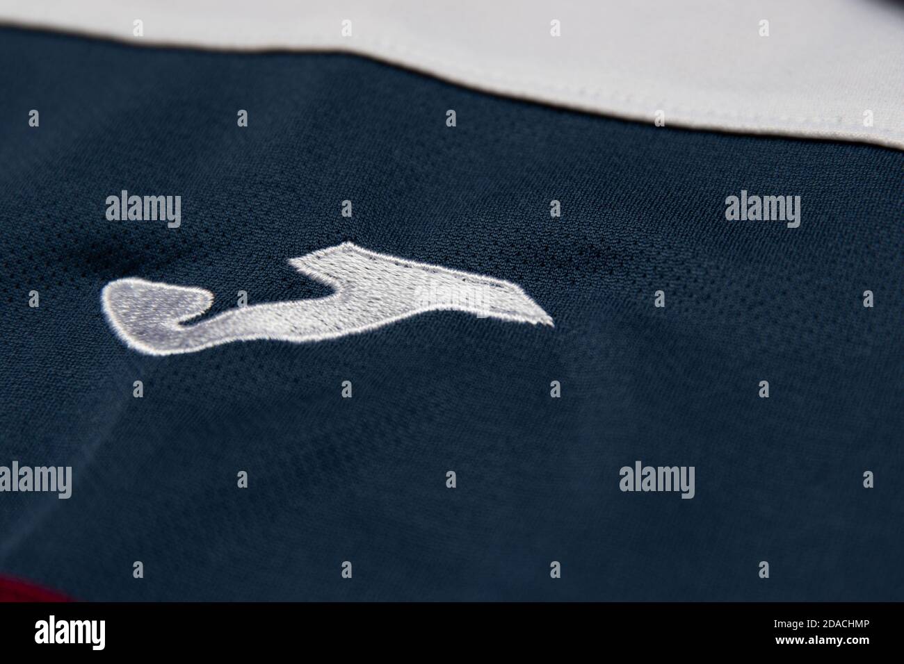 Silver White Joma logo embroidered into a dark shirt Stock Photo - Alamy
