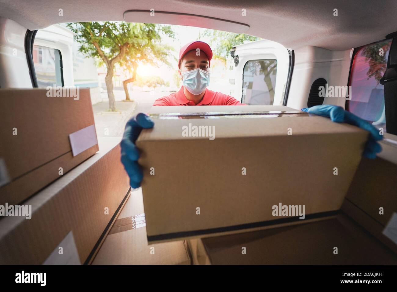 Delivery man picking up box from van while wearing face mask - Focus on ...