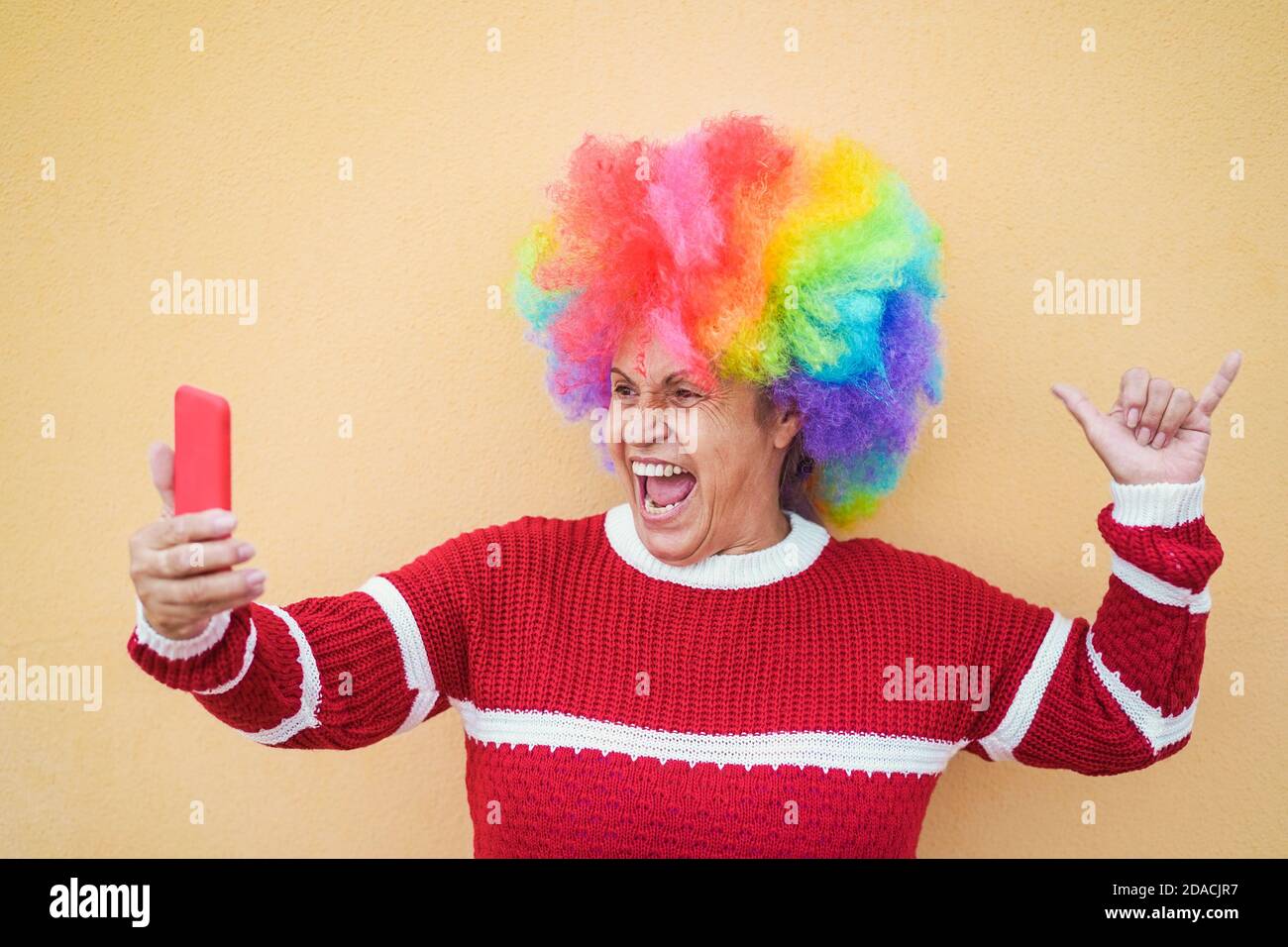 Crazy senior woman using mobile phone while listening to rock music ...