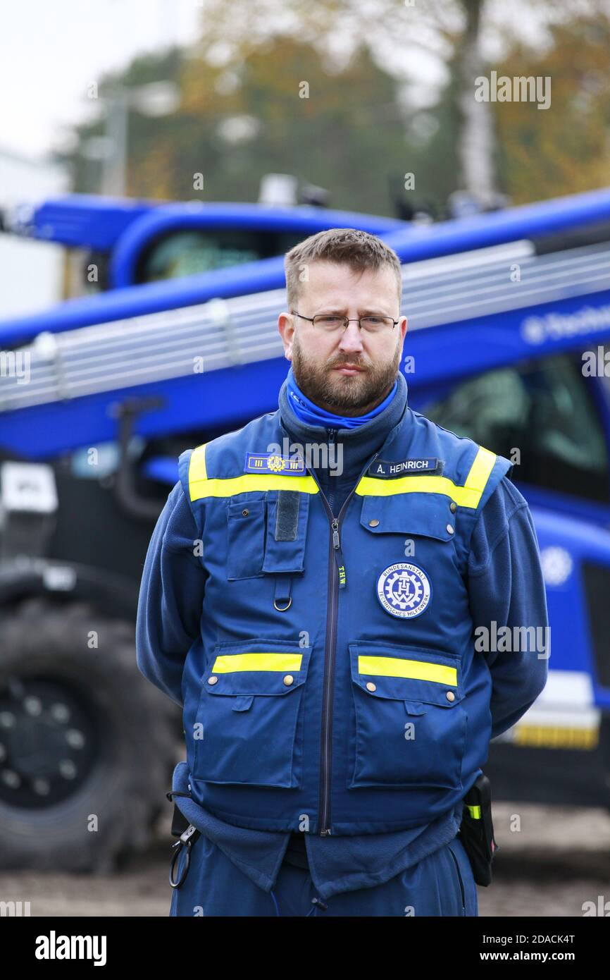 ein mitarbeiter des thw technisches hilfswerk steht vor einem fahrzeug ...