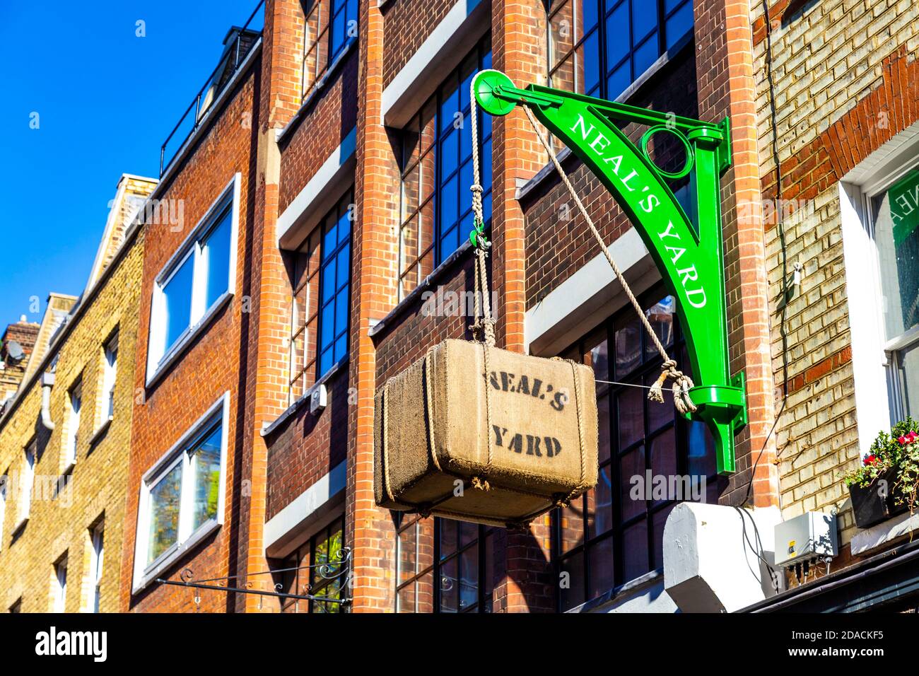 Crane lifting a parcel, sign above the entracne to Neal's Yard in ...