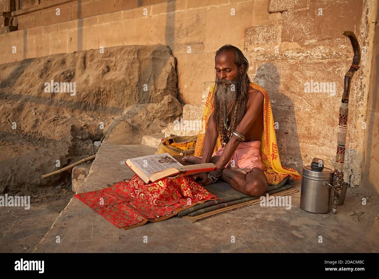 Varanasi, India, October 2011. A Sadhu reads a holy book in a ghat on ...