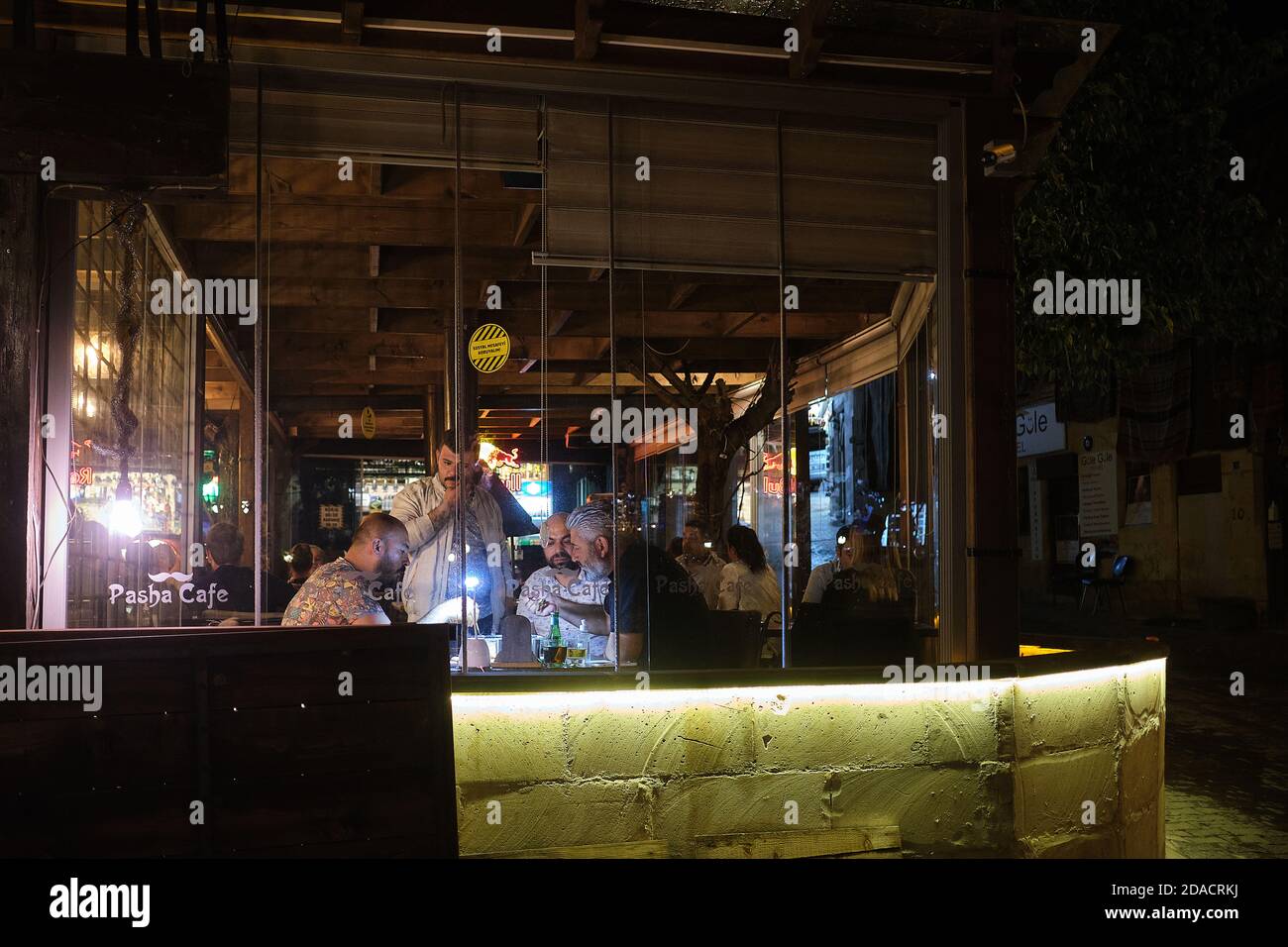 Group of male friends drinking and eating at night in Pasha Cafe ...