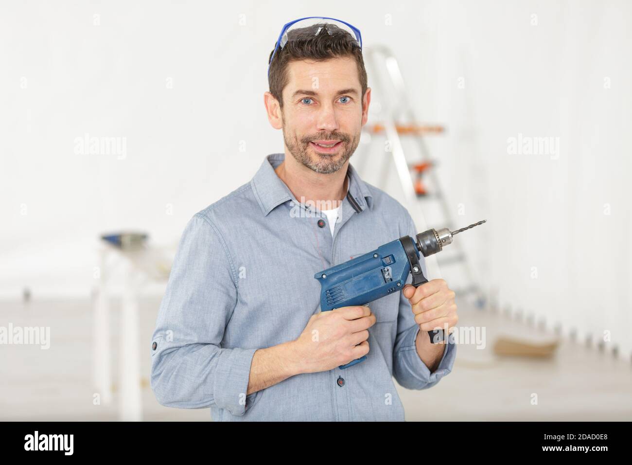 male builder drilling holes in wall at construction site Stock Photo ...