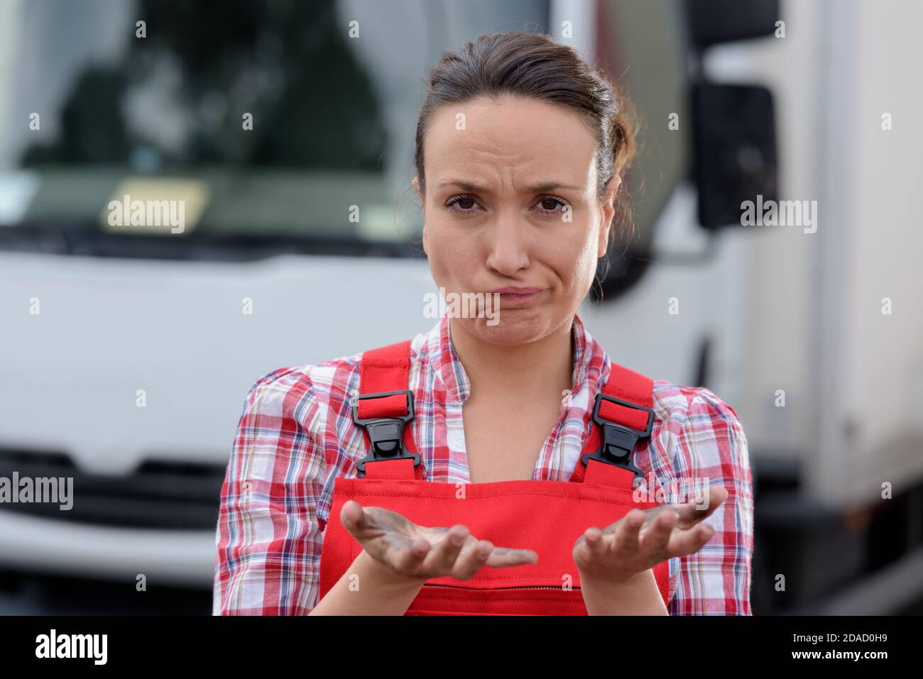 female worker showing dirty hands and making rueful facial expression ...