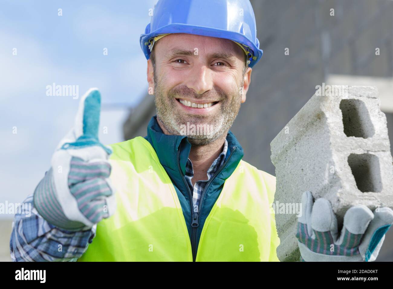builder carrying block and making thumbs up gesture Stock Photo - Alamy