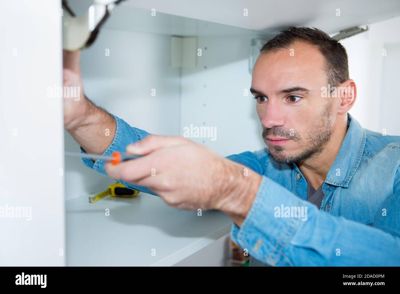 a man fitting a cupboard Stock Photo - Alamy