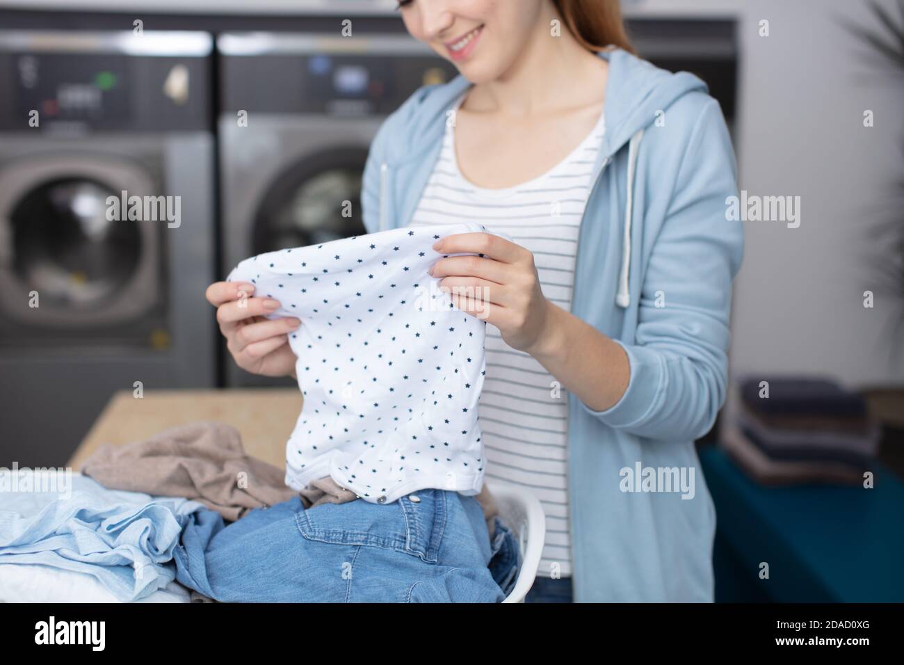 young woman sorting laundry in a laundromat Stock Photo - Alamy