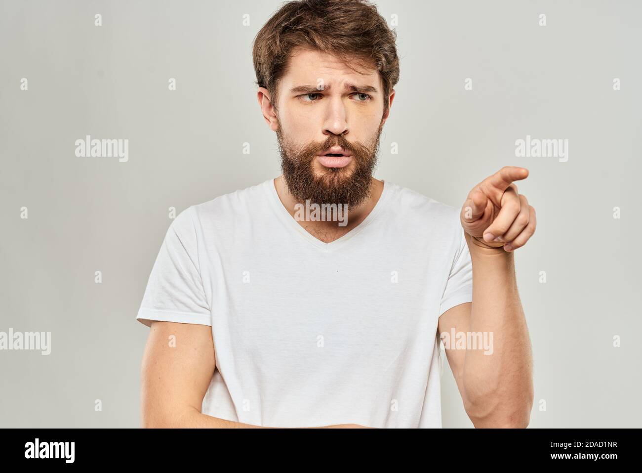 A man in a white t-shirt with a beard emotions displeased facial ...
