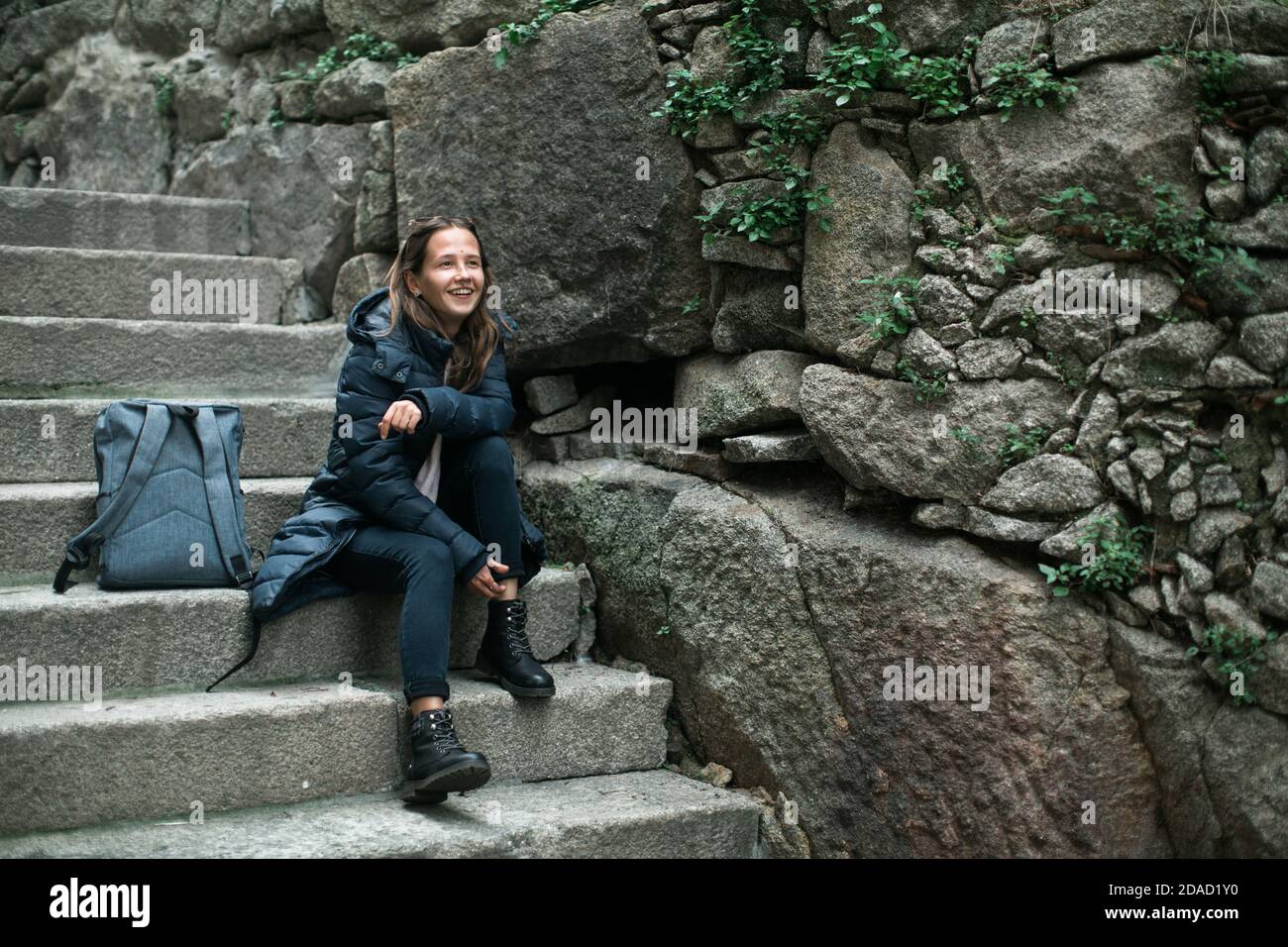 Young woman sits on the steps of an ancient stone staircase in the old ...