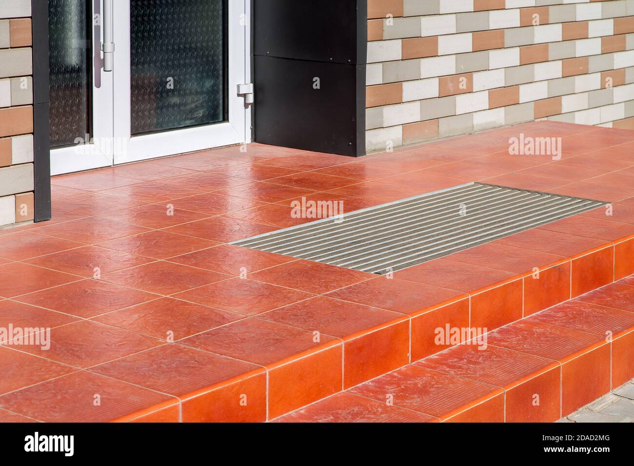 threshold with a paved red tile and a foot mat at the front door of a ...