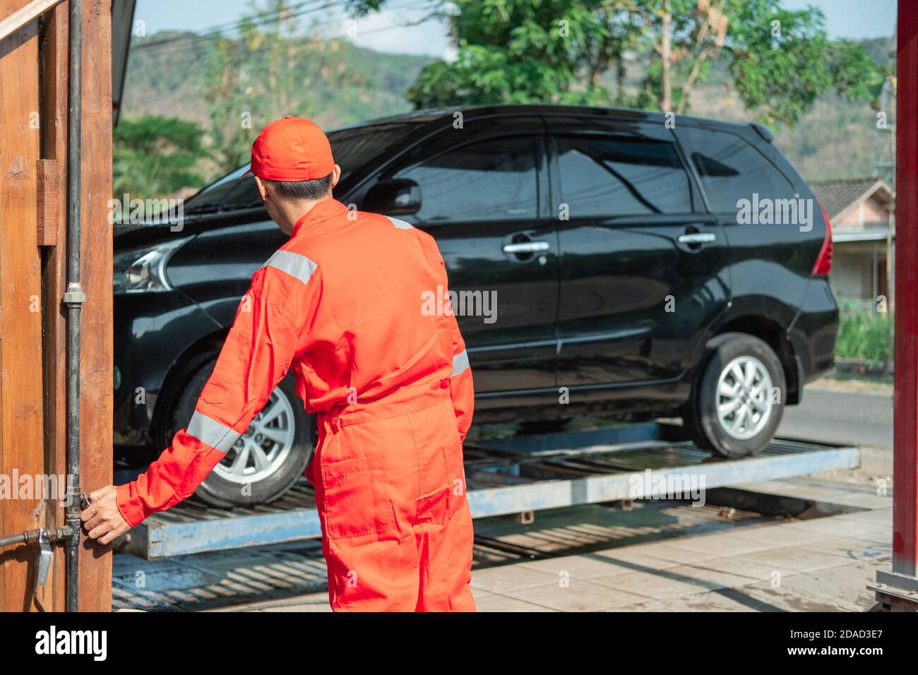 male car cleaner wearing the red uniform and the hat set the faucet to ...
