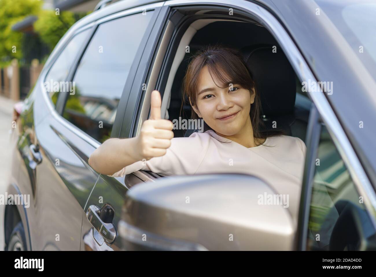 Asian happy young beautiful woman driving a car and thumb up in front ...