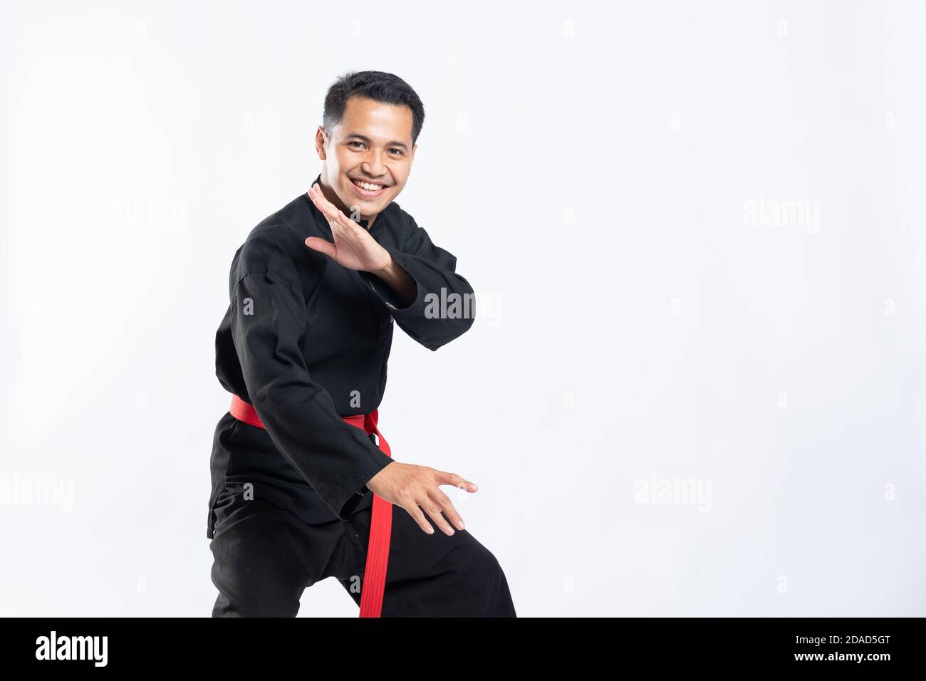 smiling Asian men wearing pencak silat uniforms stand up with pasang ...