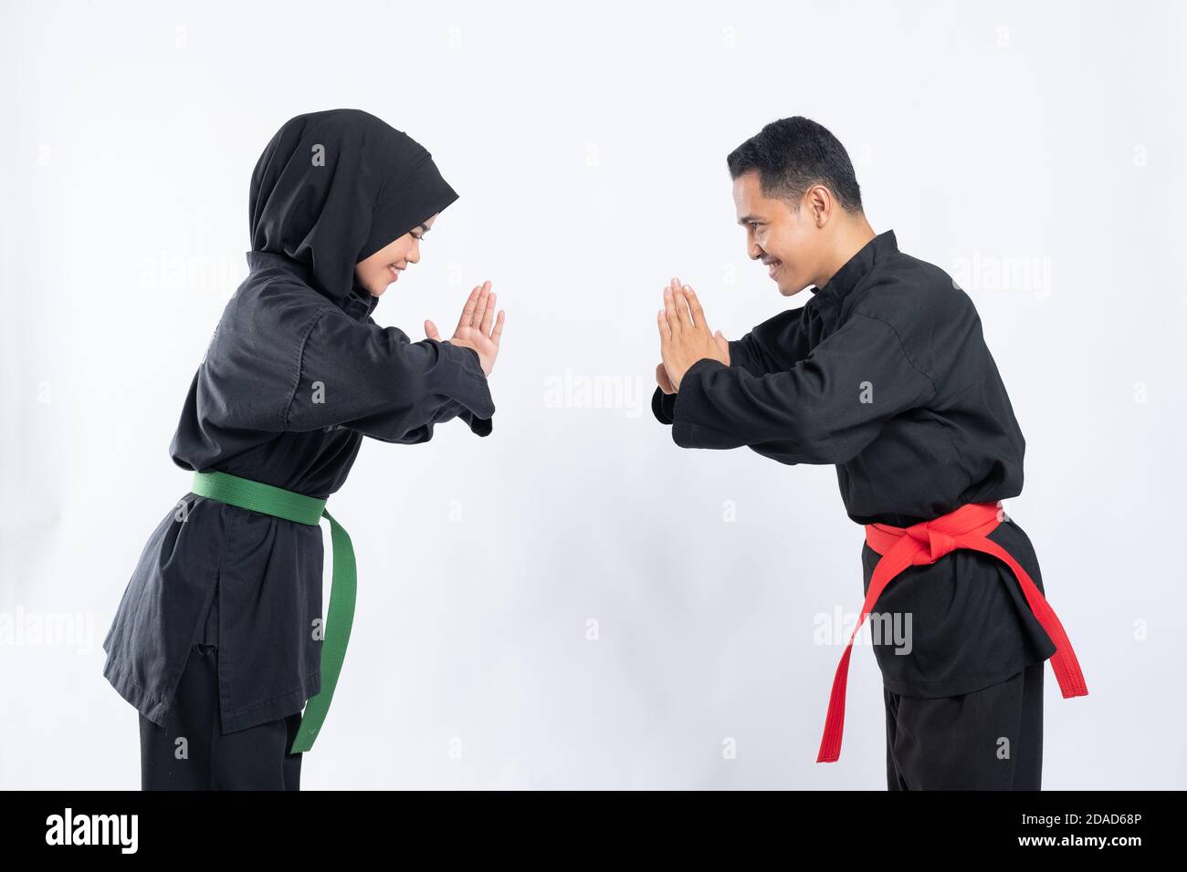 smiling Asian men and women wearing pencak silat uniforms stand face to ...