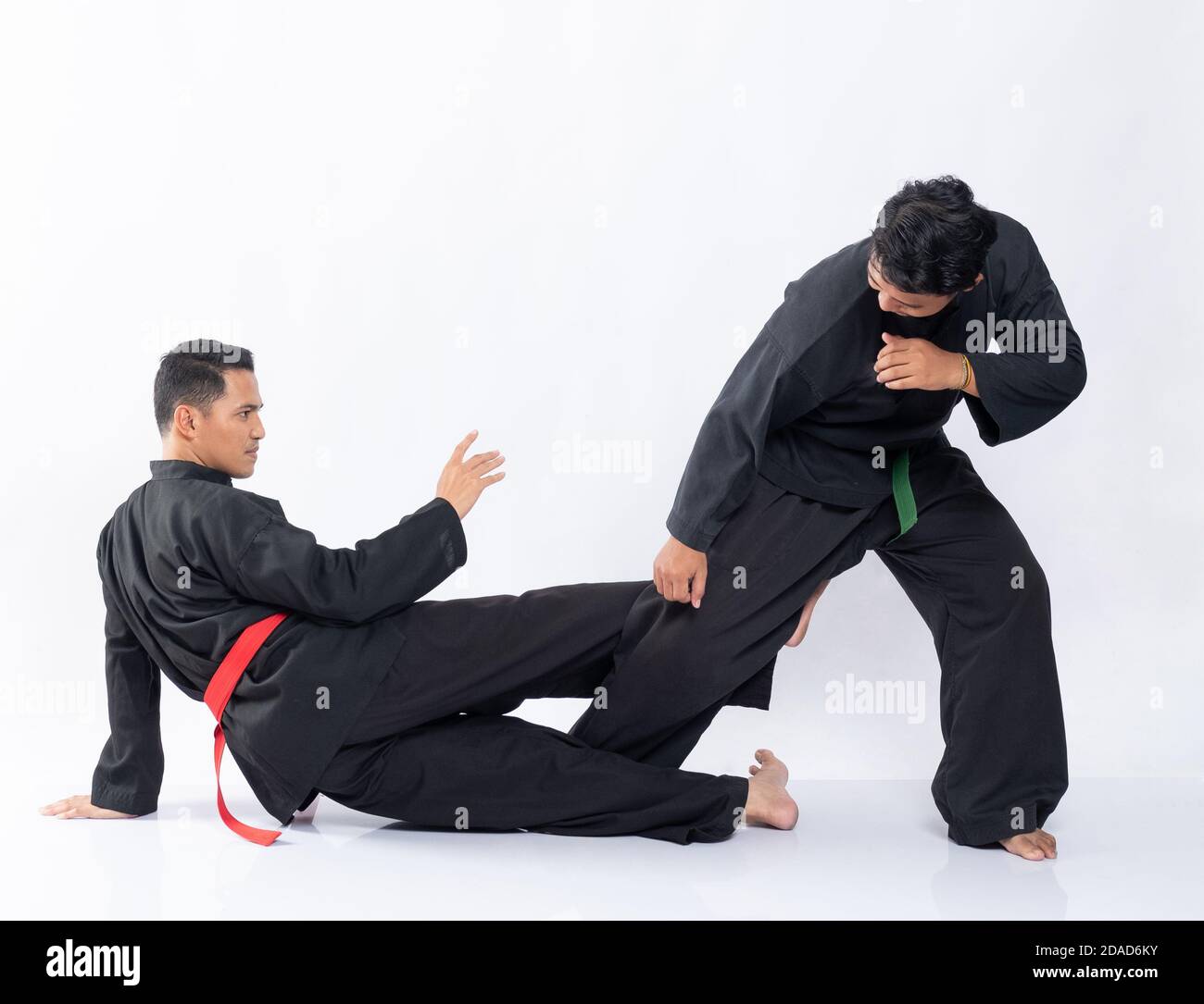 two Asian men wearing pencak silat uniforms to fight on a white ...