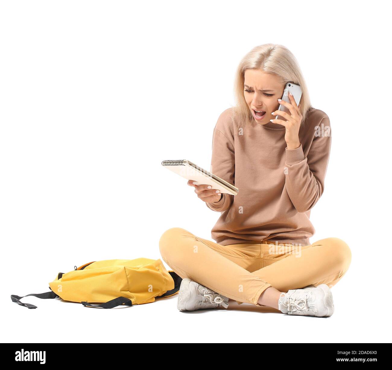 Stressed female student talking by mobile phone on white background ...