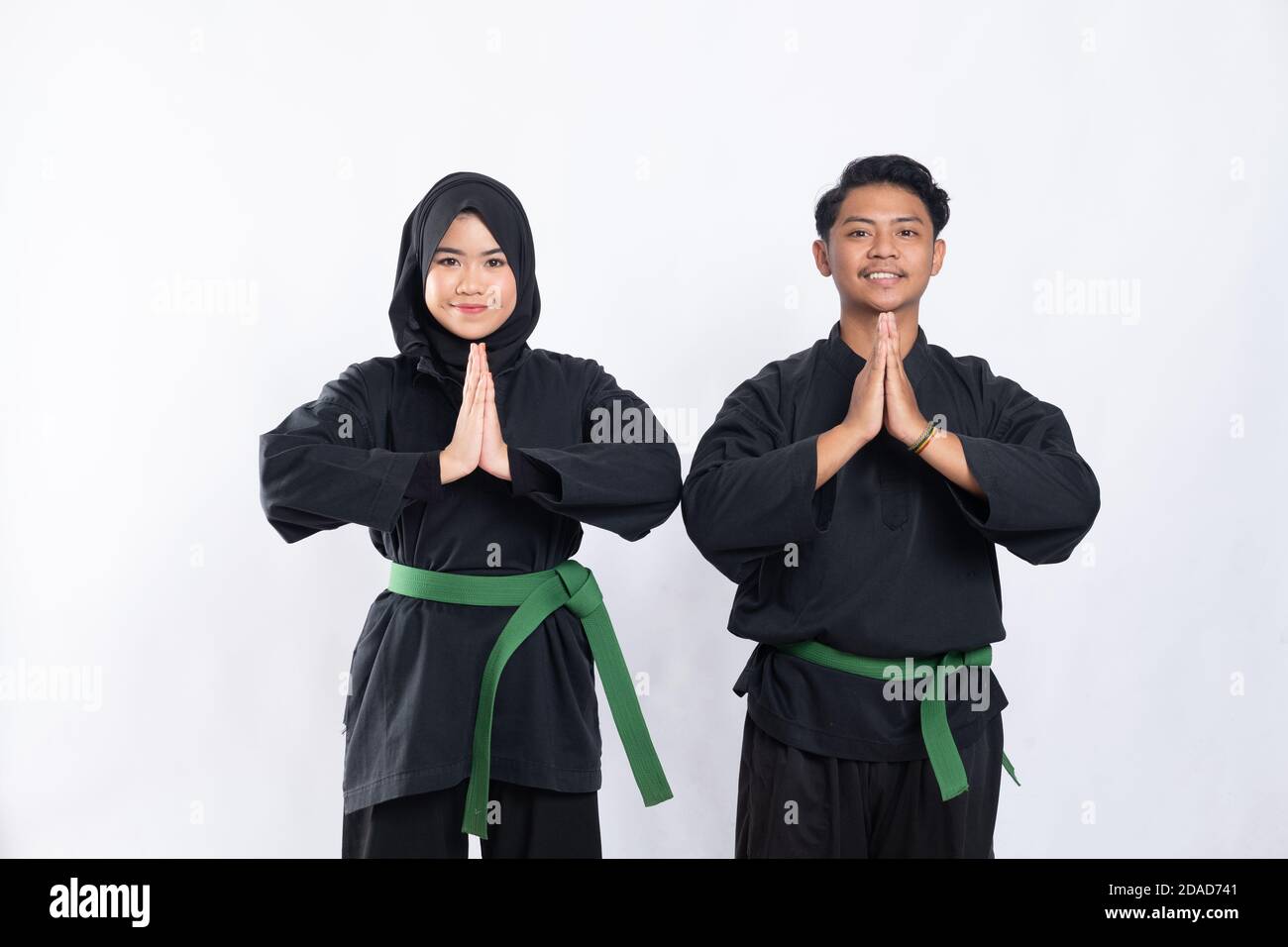 Hooded women and men in pencak silat uniform poses respectfully with ...