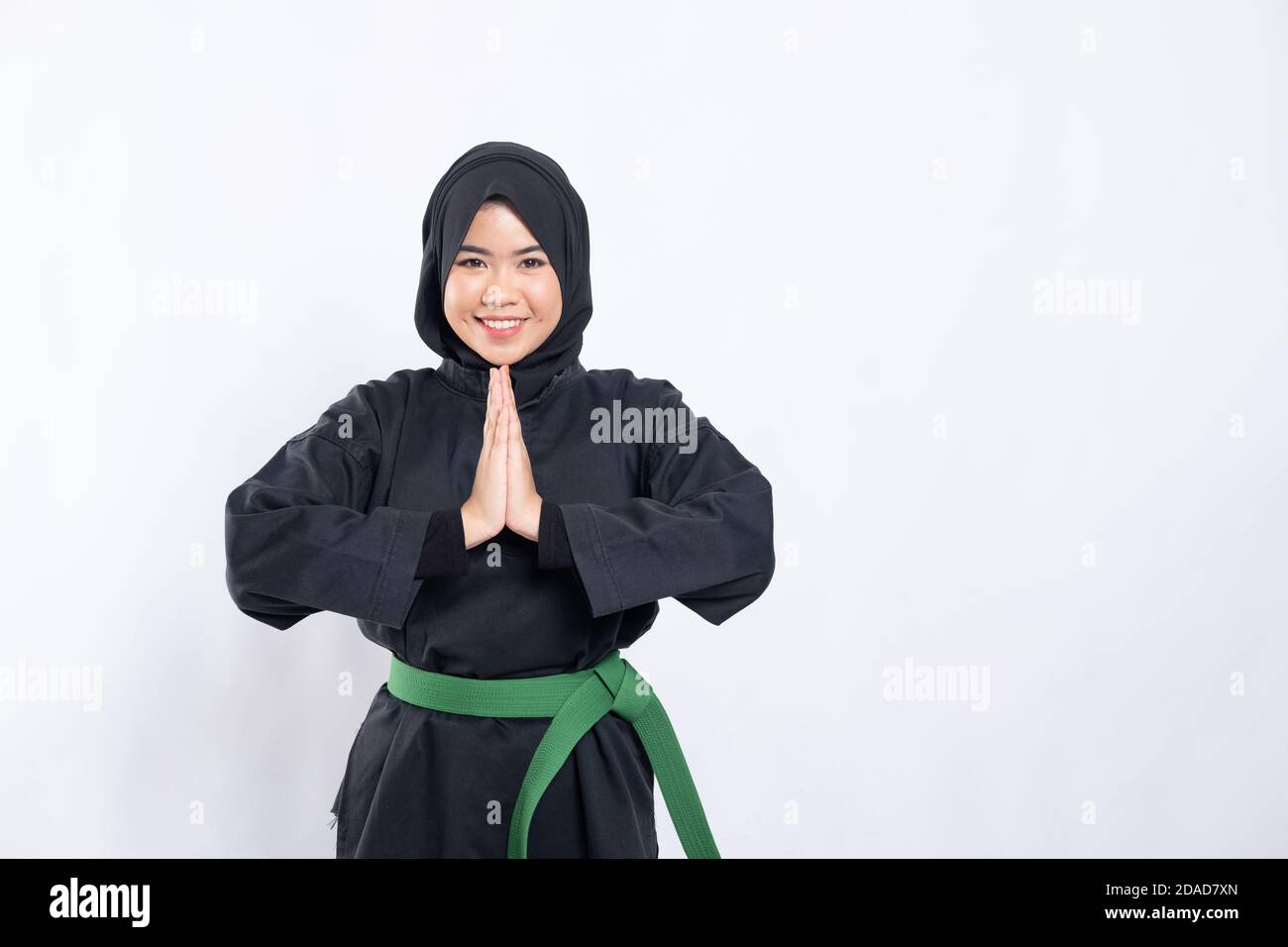 A woman in a veil in a pencak silat uniform poses respectfully with her ...