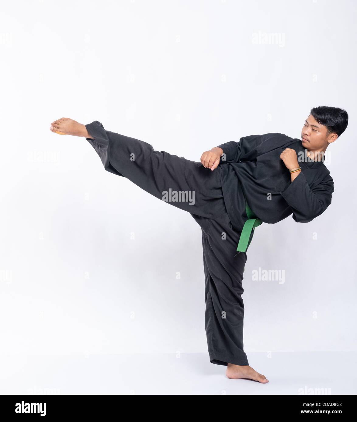 view side of a man with a kicking pose while wearing a pencak silat ...