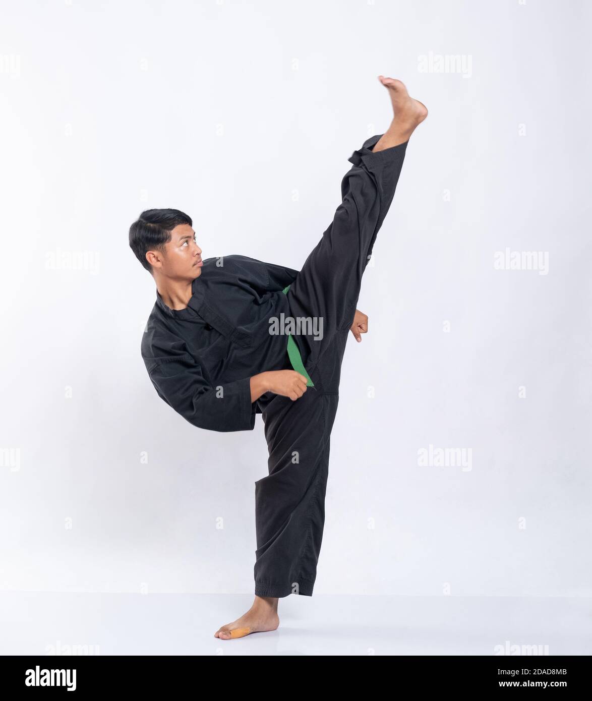 Asian men wearing pencak silat uniforms with green belts kicking one ...