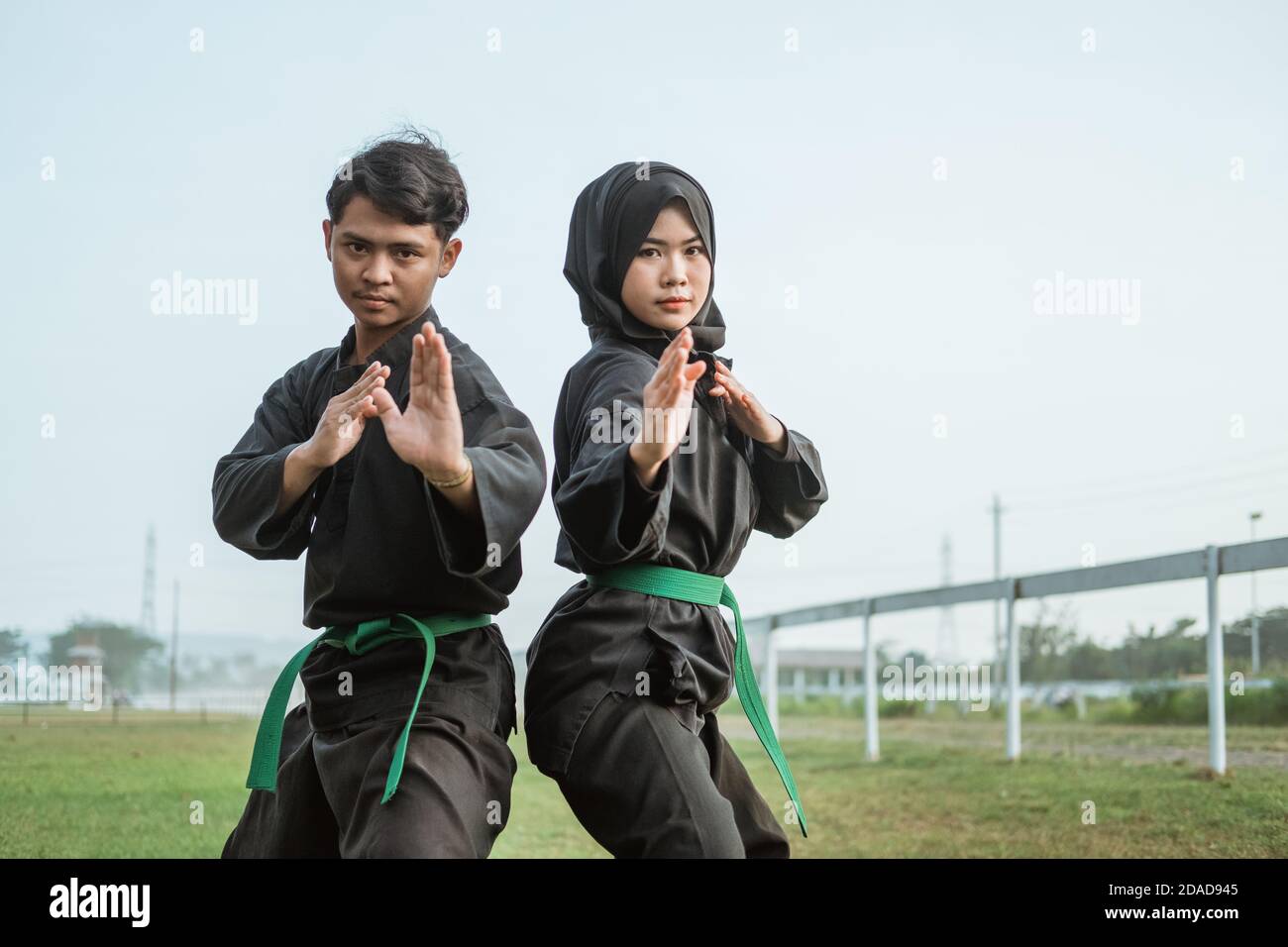 Male and female fighters wearing pencak silat uniforms perform side ...