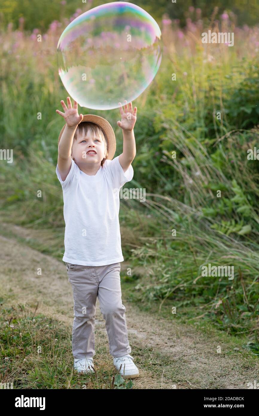 Happy boy catching soap bubbles in nature in summer Stock Photo - Alamy