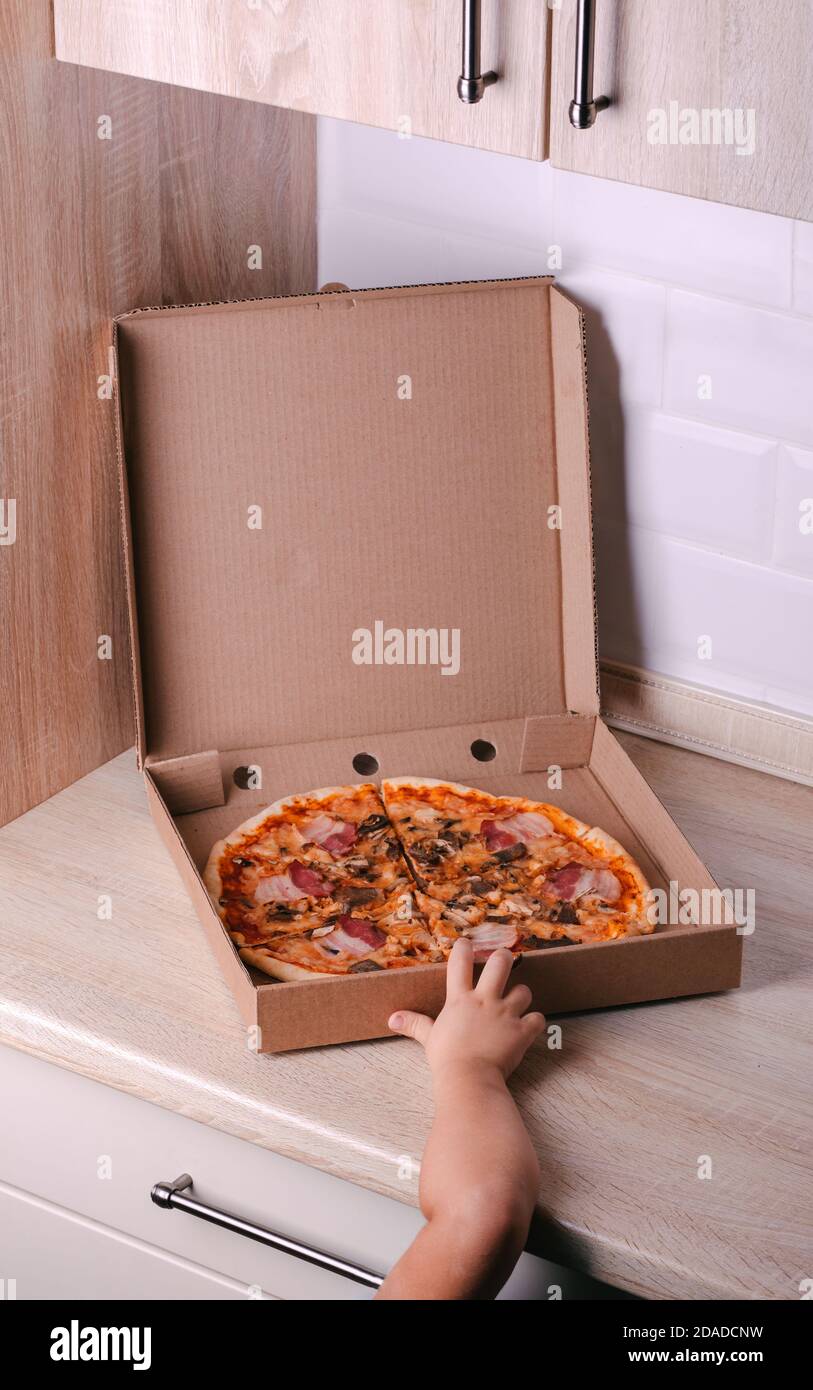 The child tries to steal a slice of pizza from the box. Food delivery ...