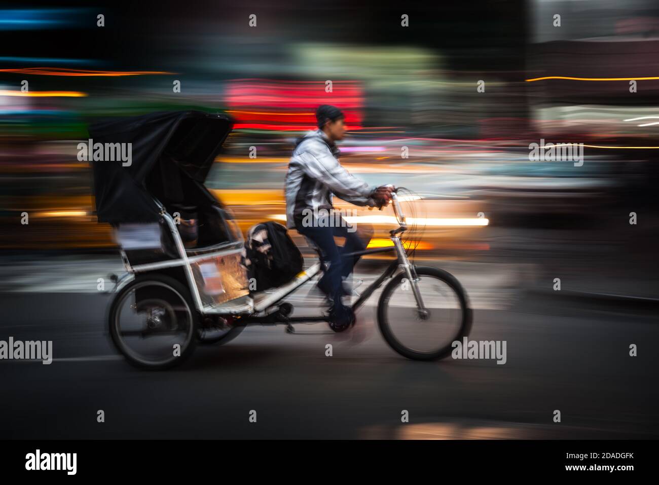 Man riding a traditional tricycle on a street. Illumination and night ...